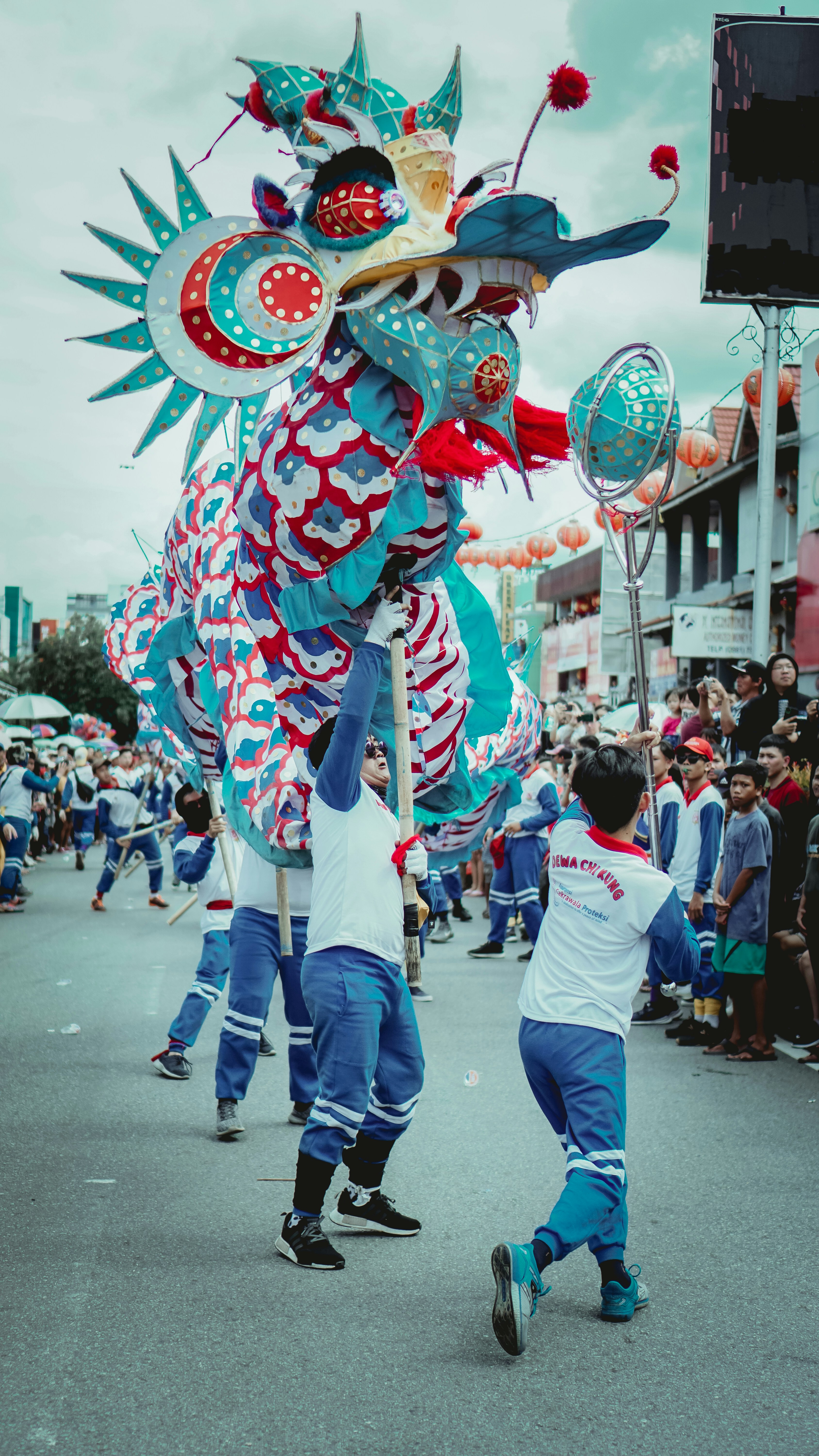 Colorful dragon puppet held aloft by performers in a lively street parade.