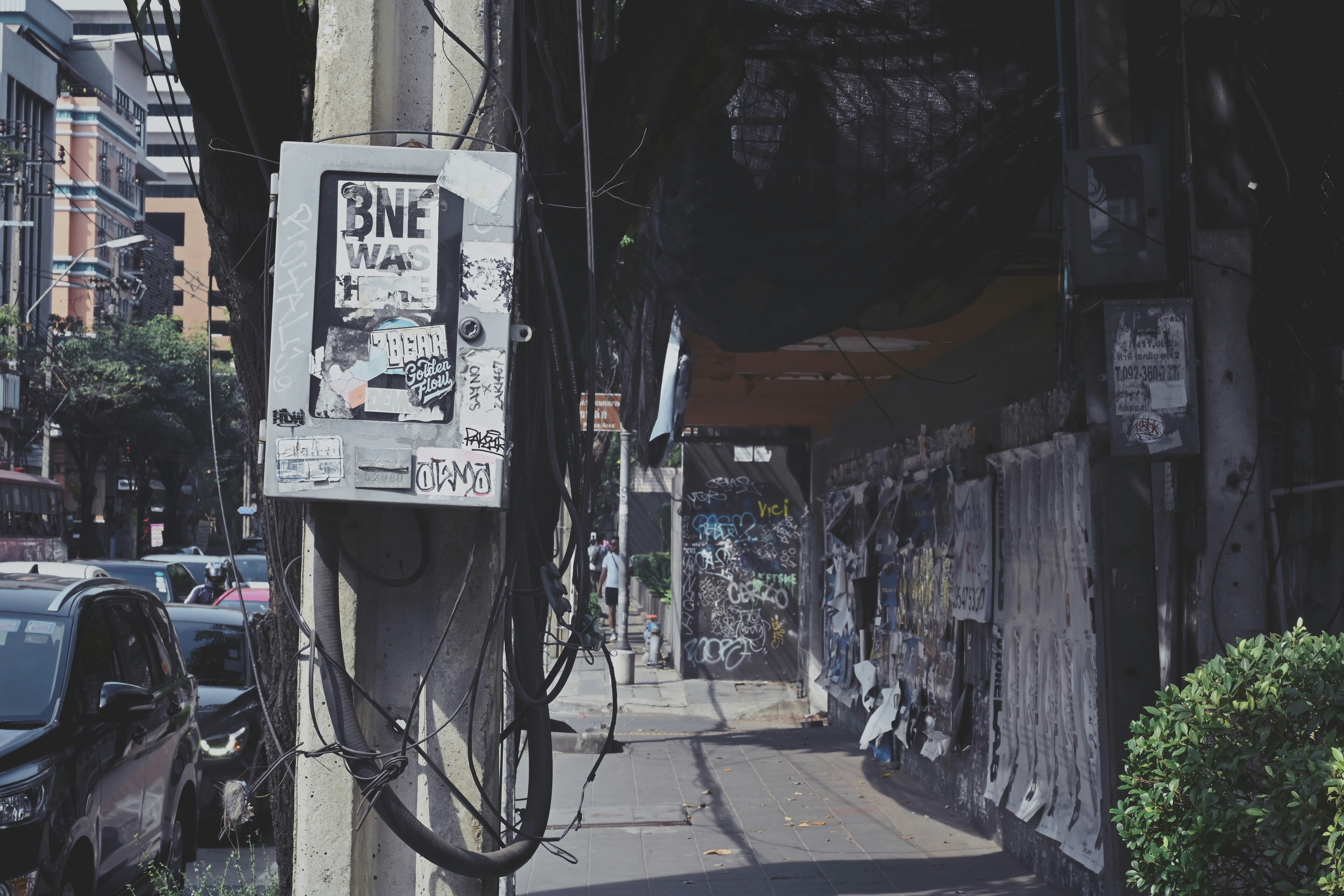 Utility pole adorned with eclectic stickers and graffiti, juxtaposed against a cityscape backdrop. The scene captures the essence of urban artistry.