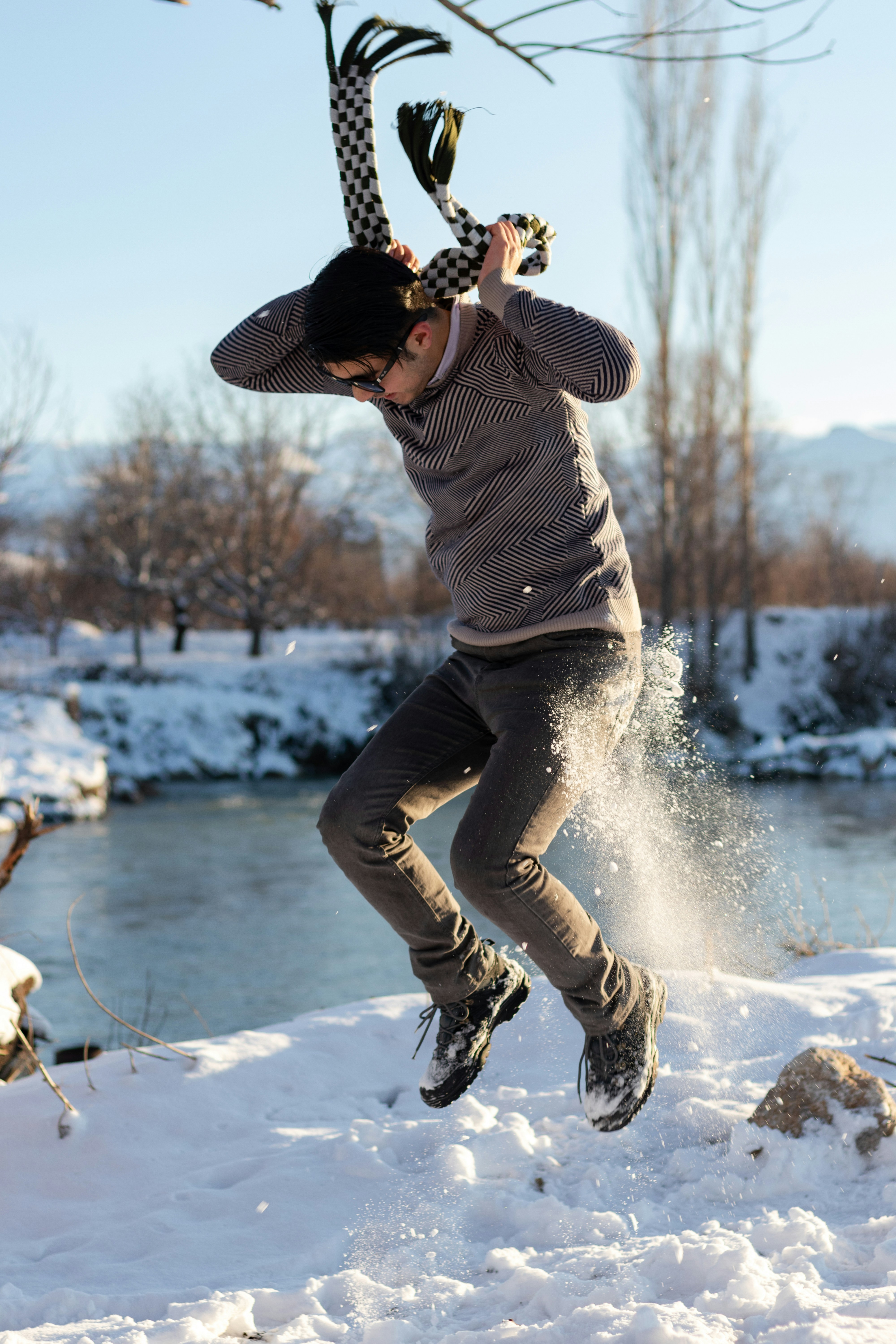 Midair Leap by a Striped Jumper Over a Snow-Covered Riverbank