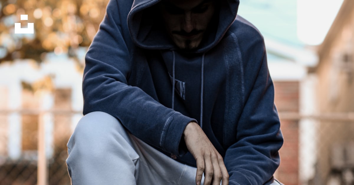 昼間にコンクリートのベンチに座っている黒いパーカーと灰色のズボンを着た男性の写真 Unsplashの人間の無料画像