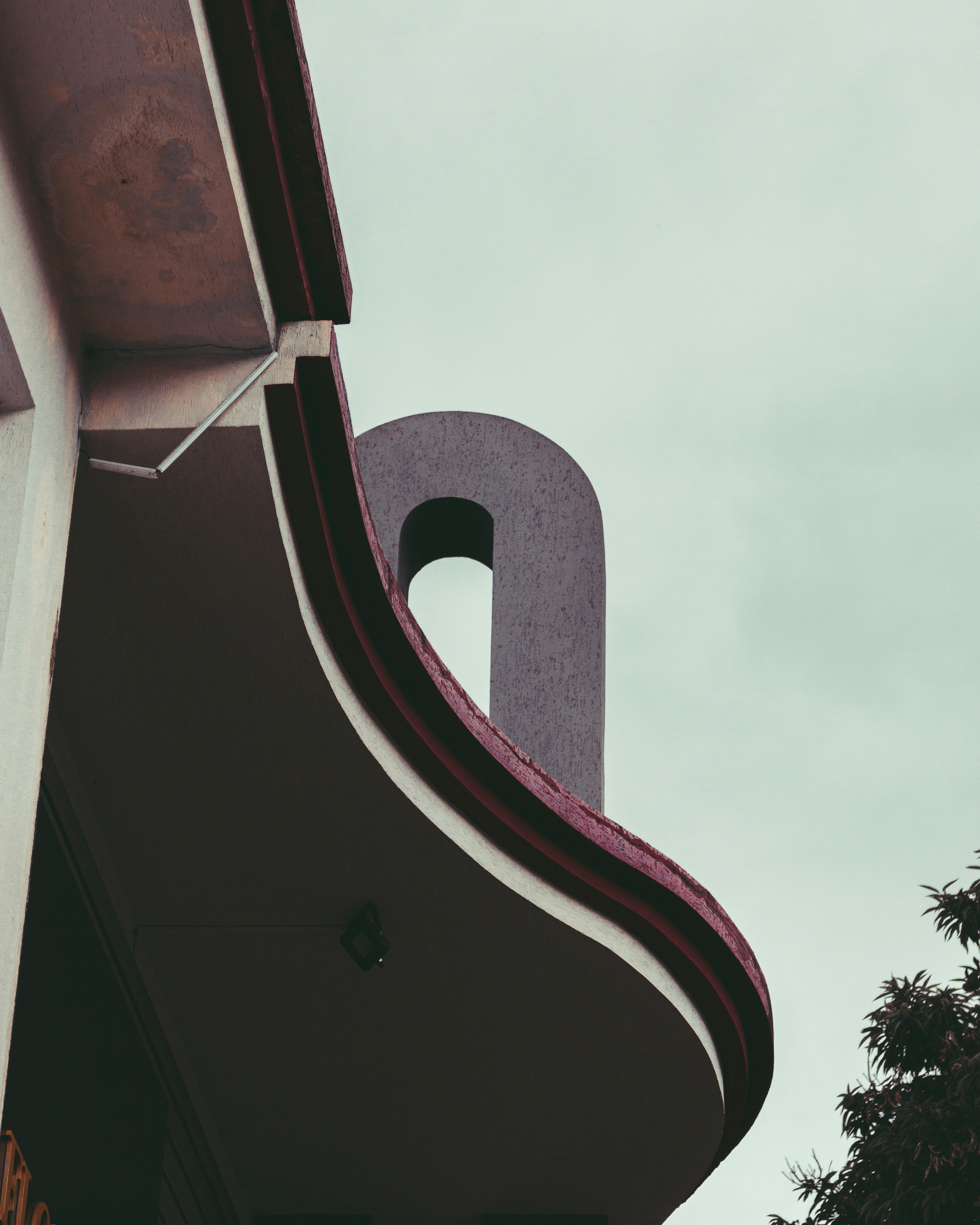 Curved Heritage: A Red-Rimmed Balcony Ripples Against a Pale Sky