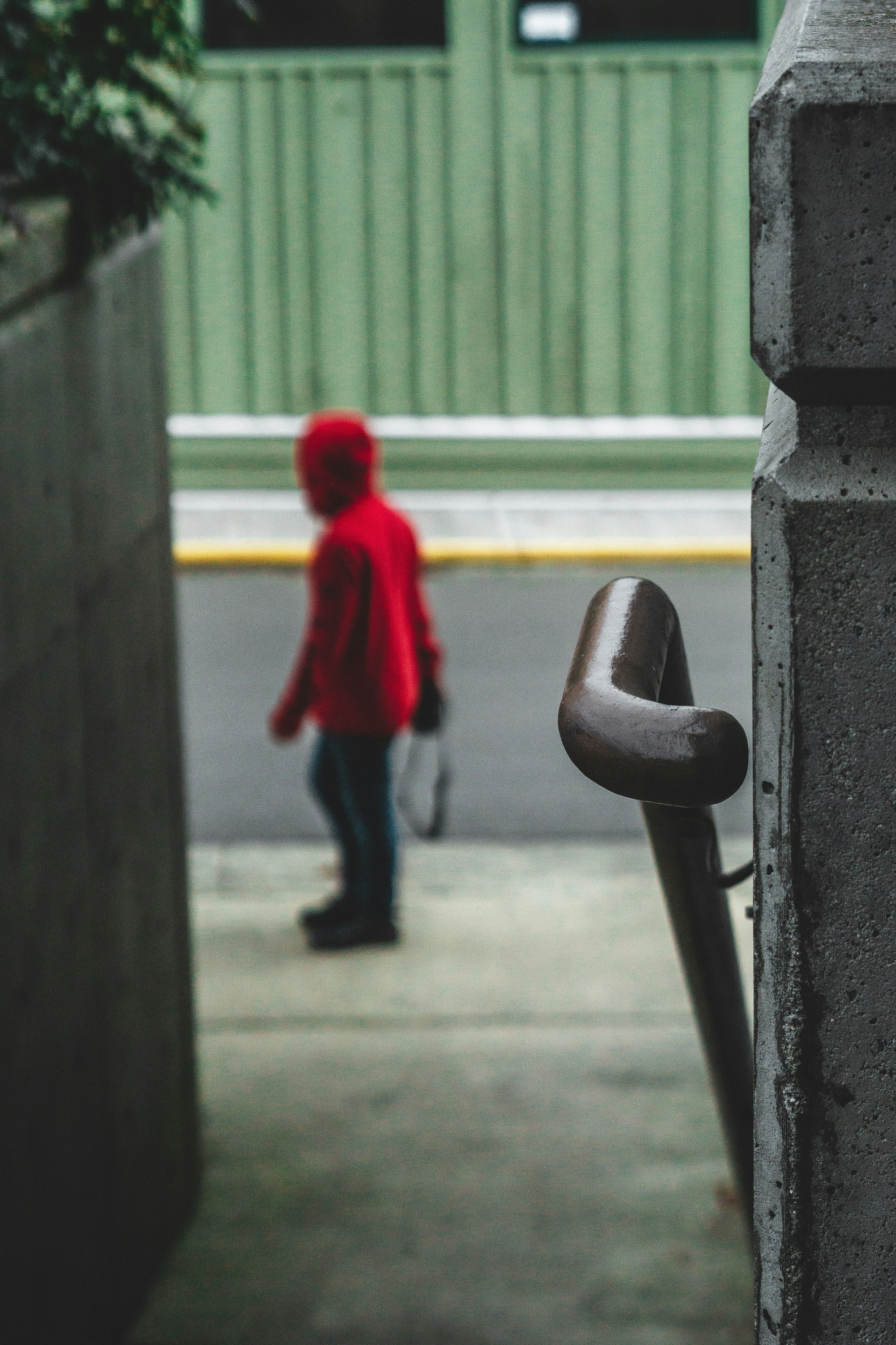 Red Hood in the Corridor: A Quiet Street Scene Framed by Concrete and Green