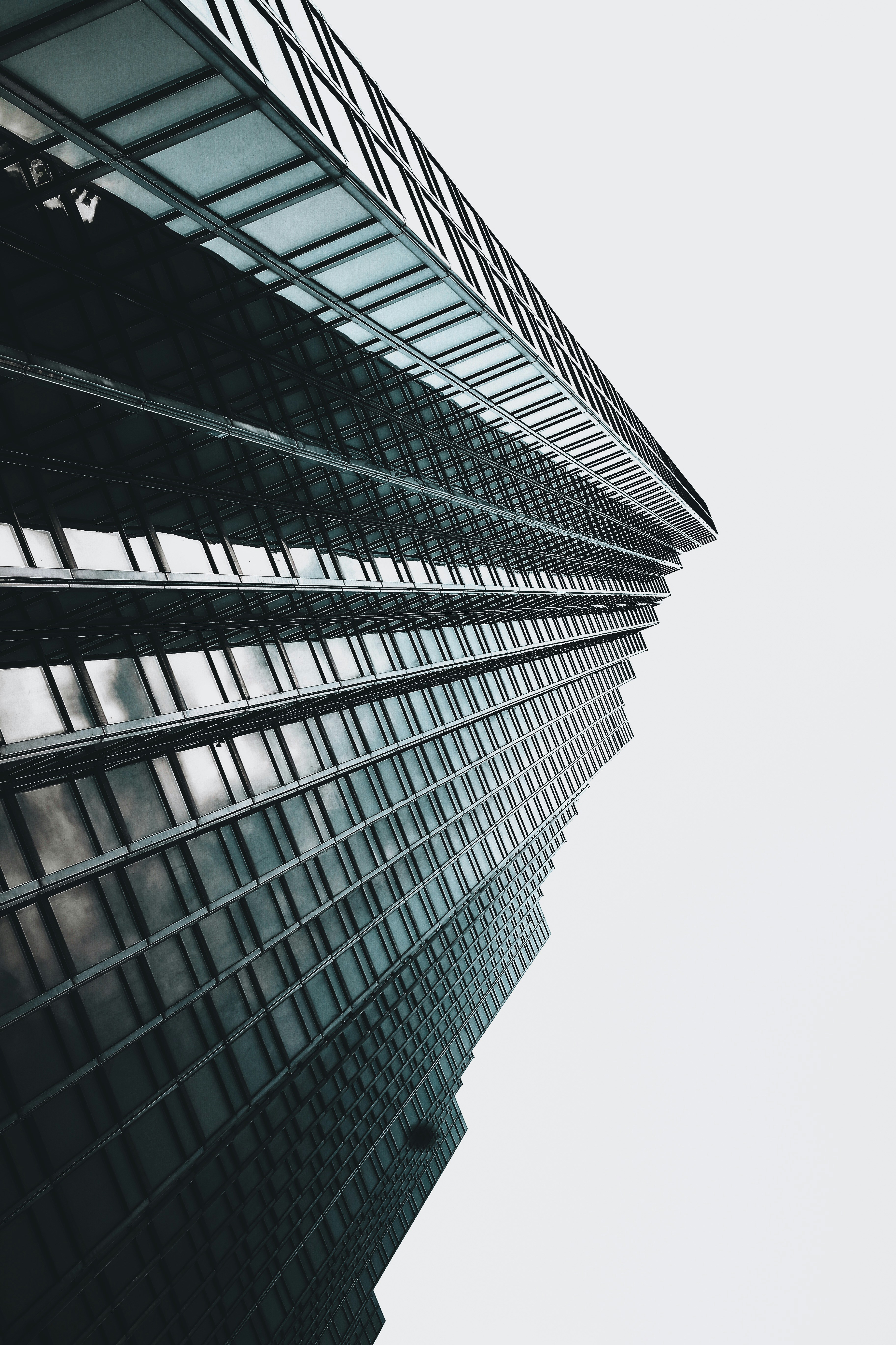 A sleek skyscraper's glass facade reflects the sky, captured from a low angle to emphasize its towering height.