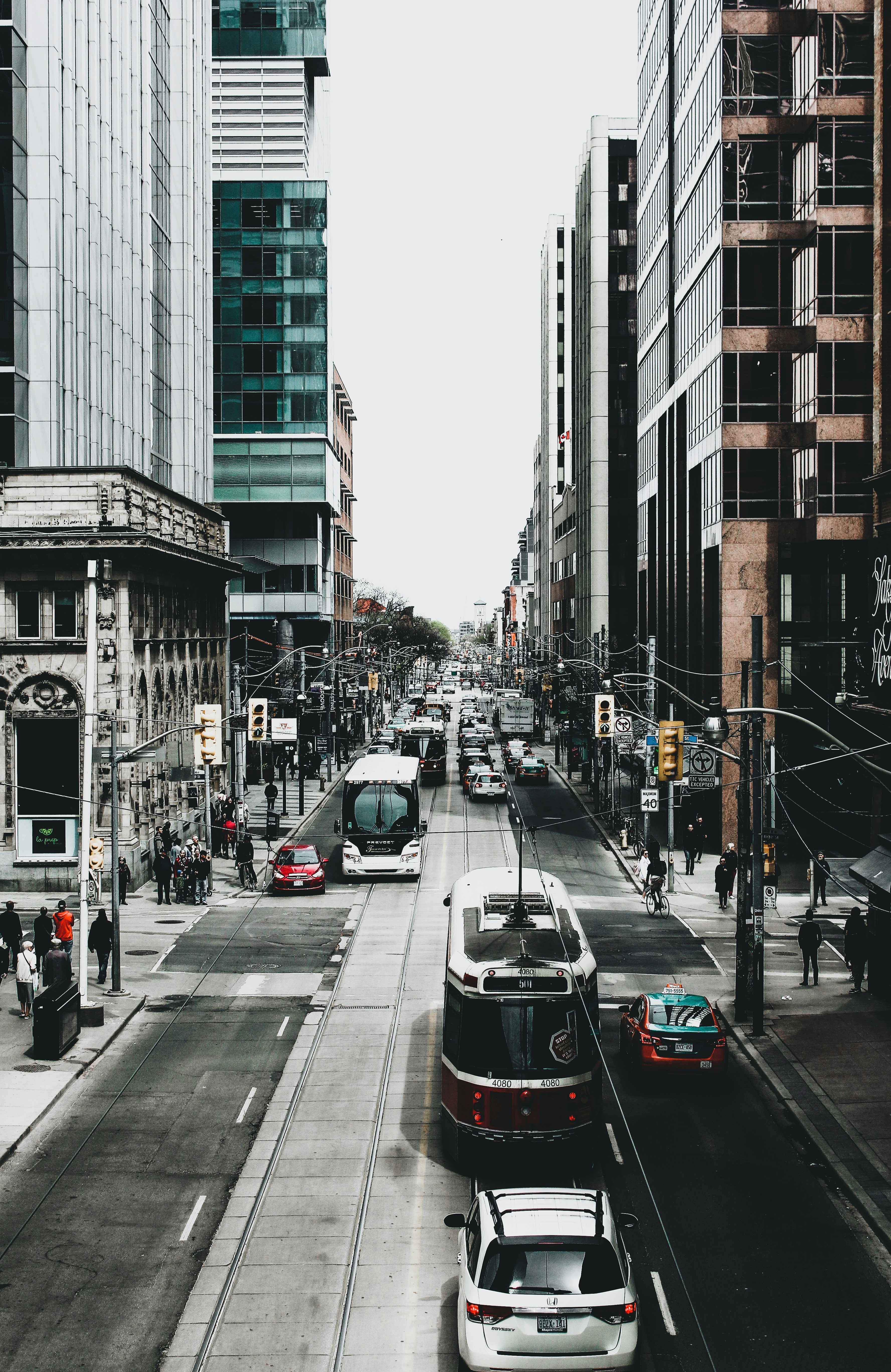 Busy urban street scene with trams and vehicles navigating through a modern cityscape, showcasing the blend of architecture and daily life.