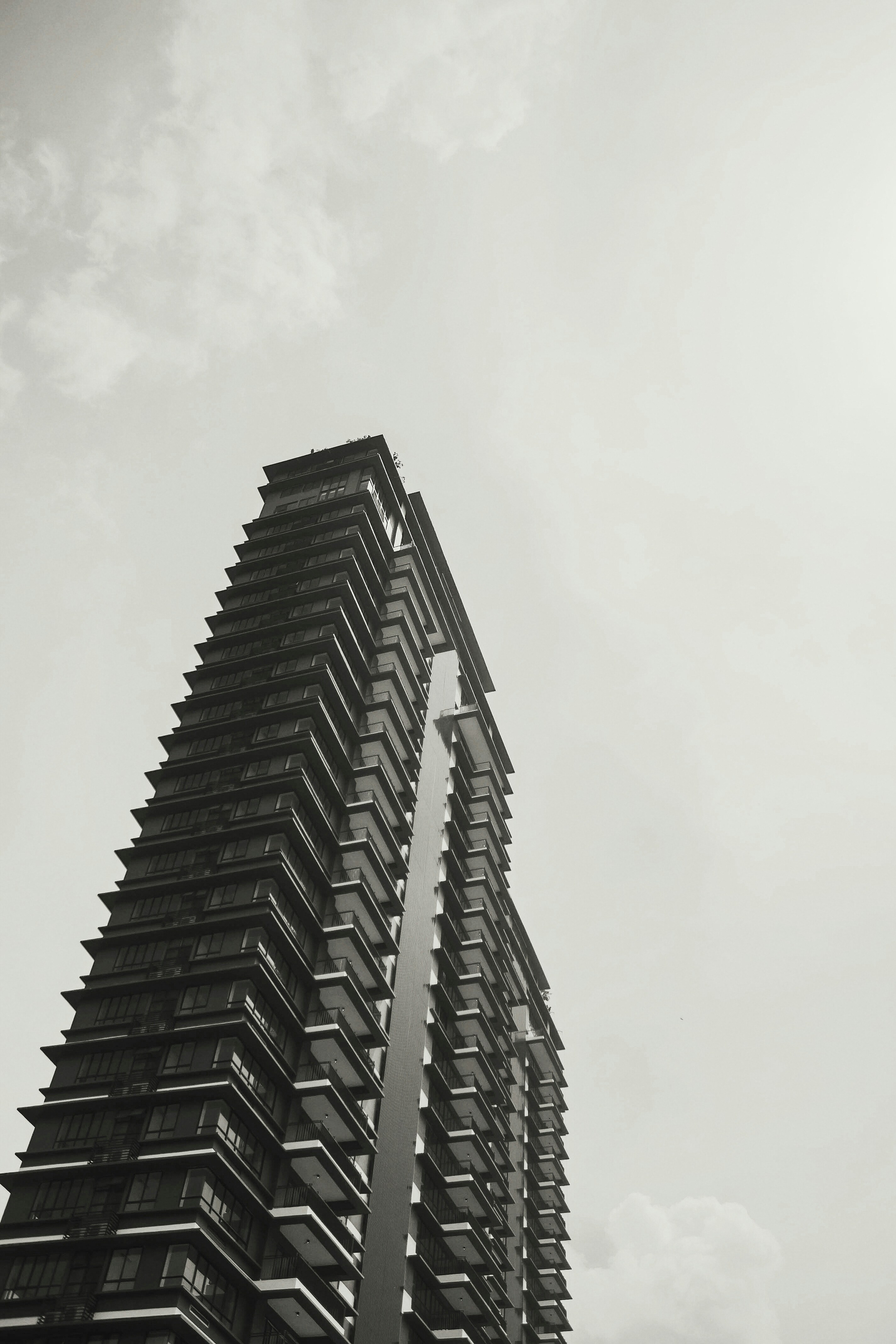 A towering residential building reaching towards the sky, captured in a monochrome palette that emphasizes its sleek lines and contemporary design.