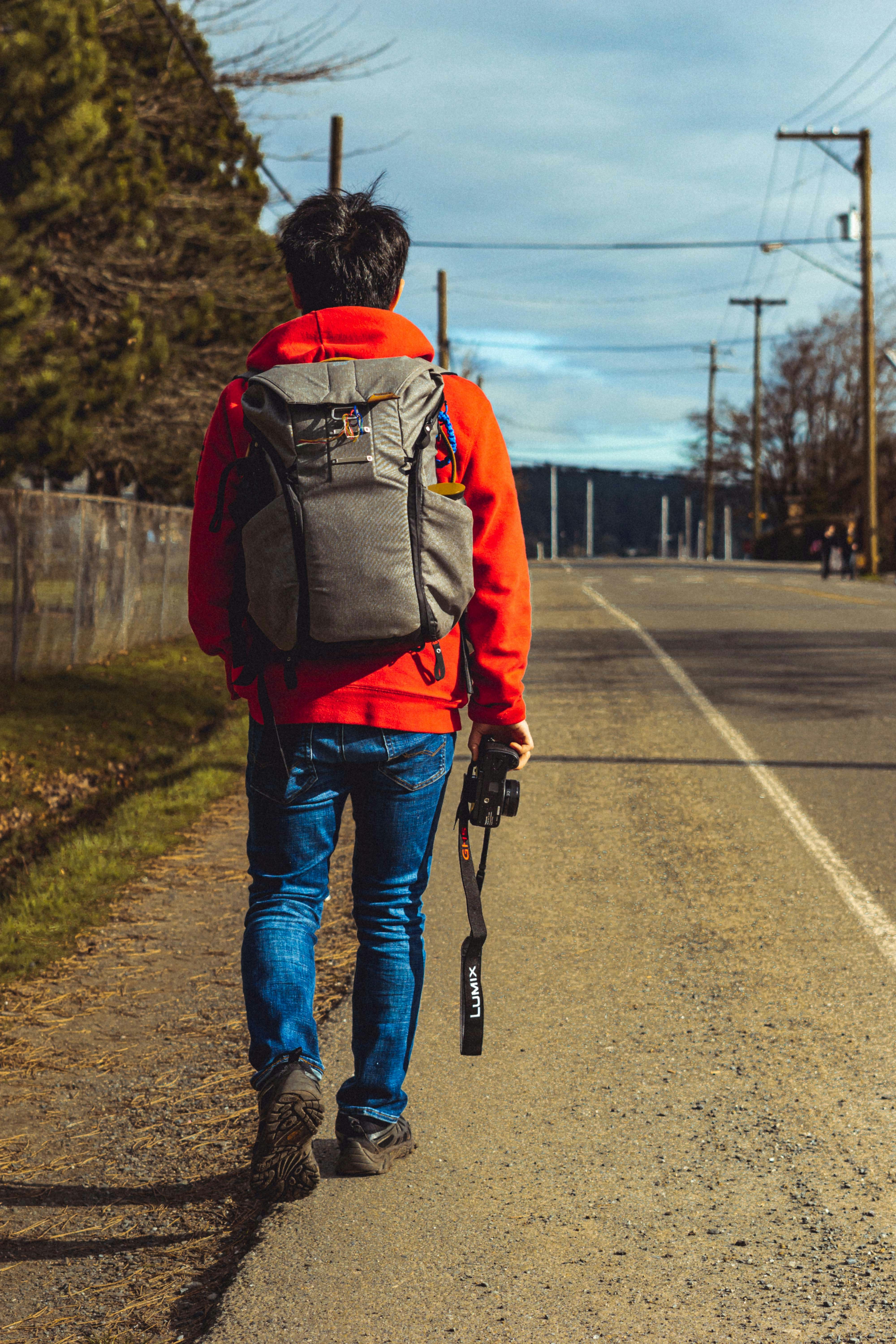 Red-Hooded Wanderer on a Quiet Road, Camera in Hand