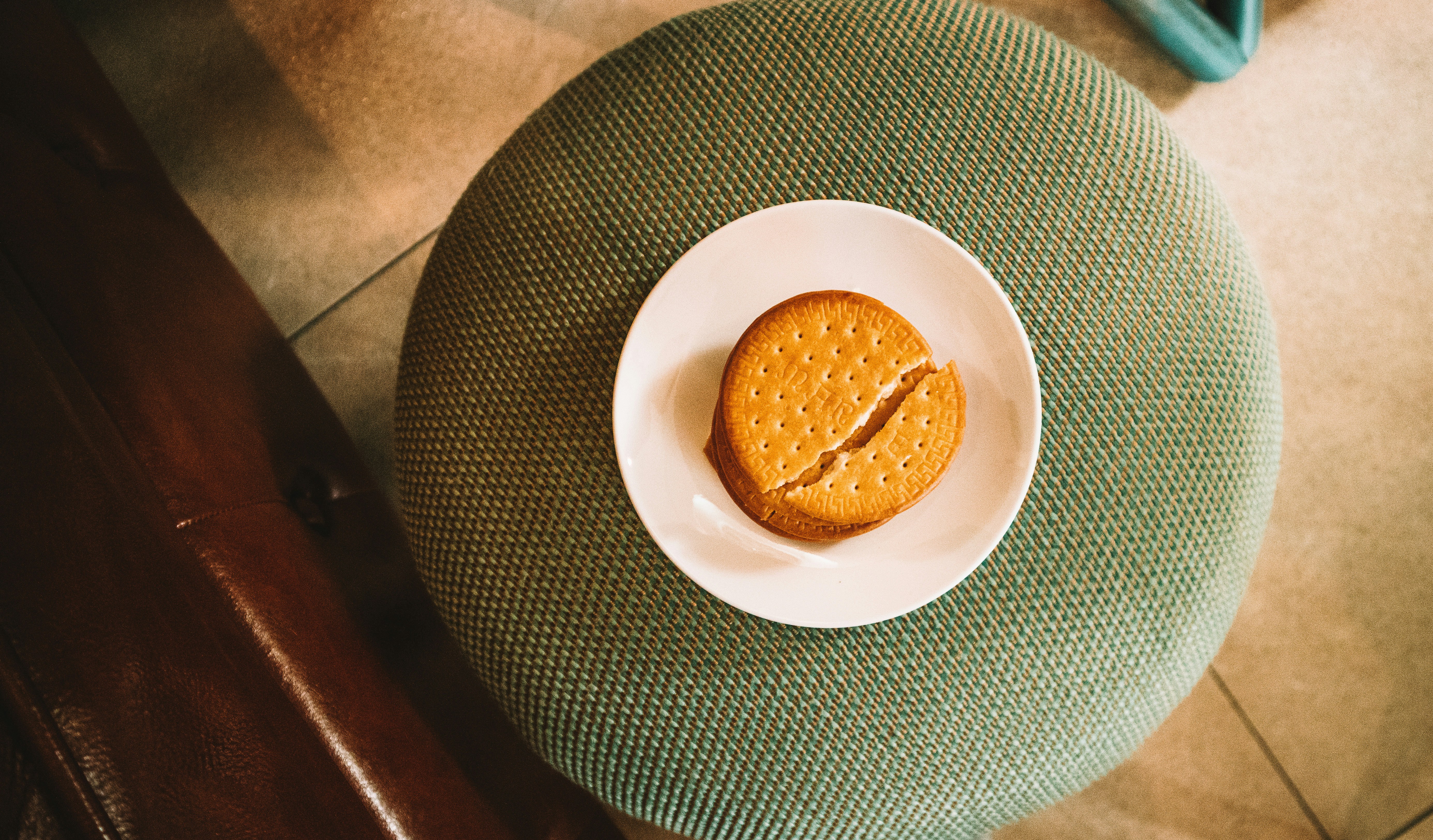 Verdant Spotlight: A Biscuit Quietly Centered on a Round Ottoman