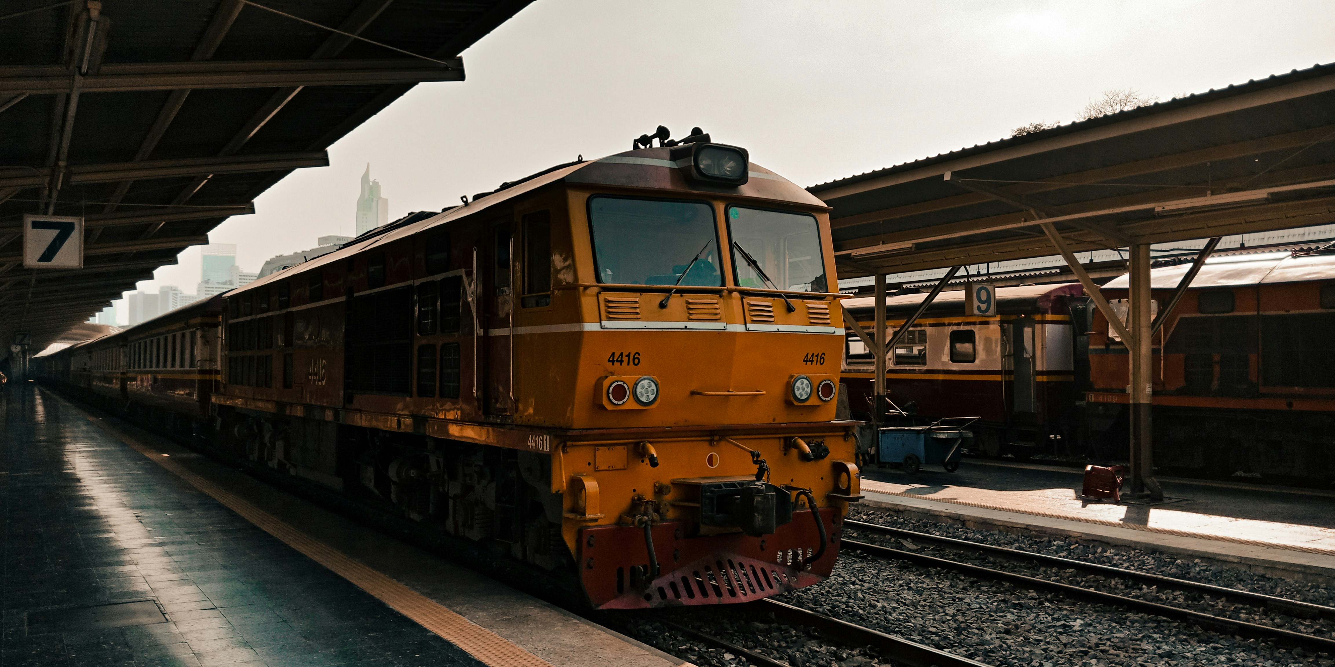 Yellow diesel locomotive sits at Platform Seven with other railcars in the background.