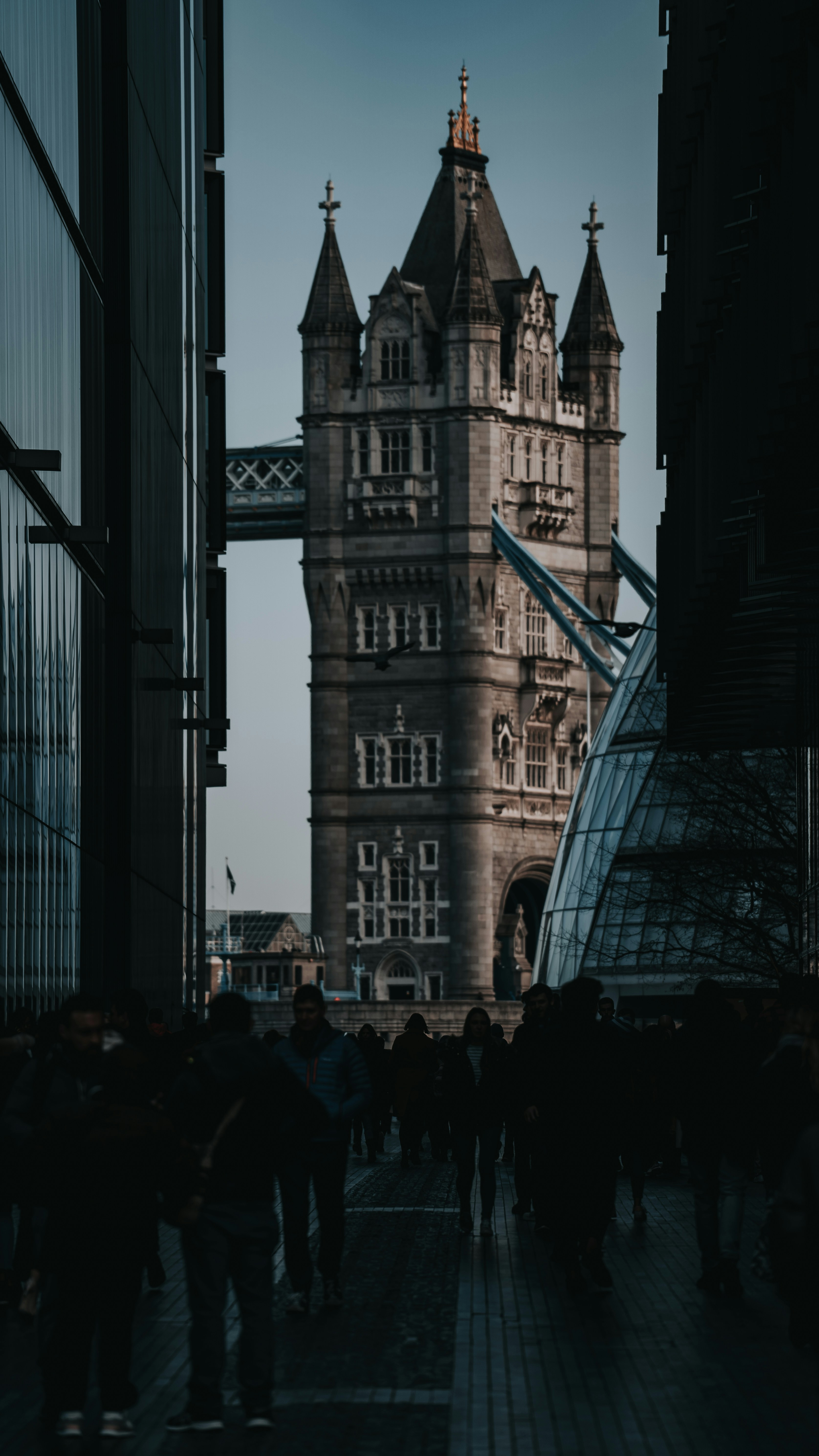Historic tower peeking through a bustling urban landscape, framed by contemporary architecture. The scene captures the contrast between old and new.