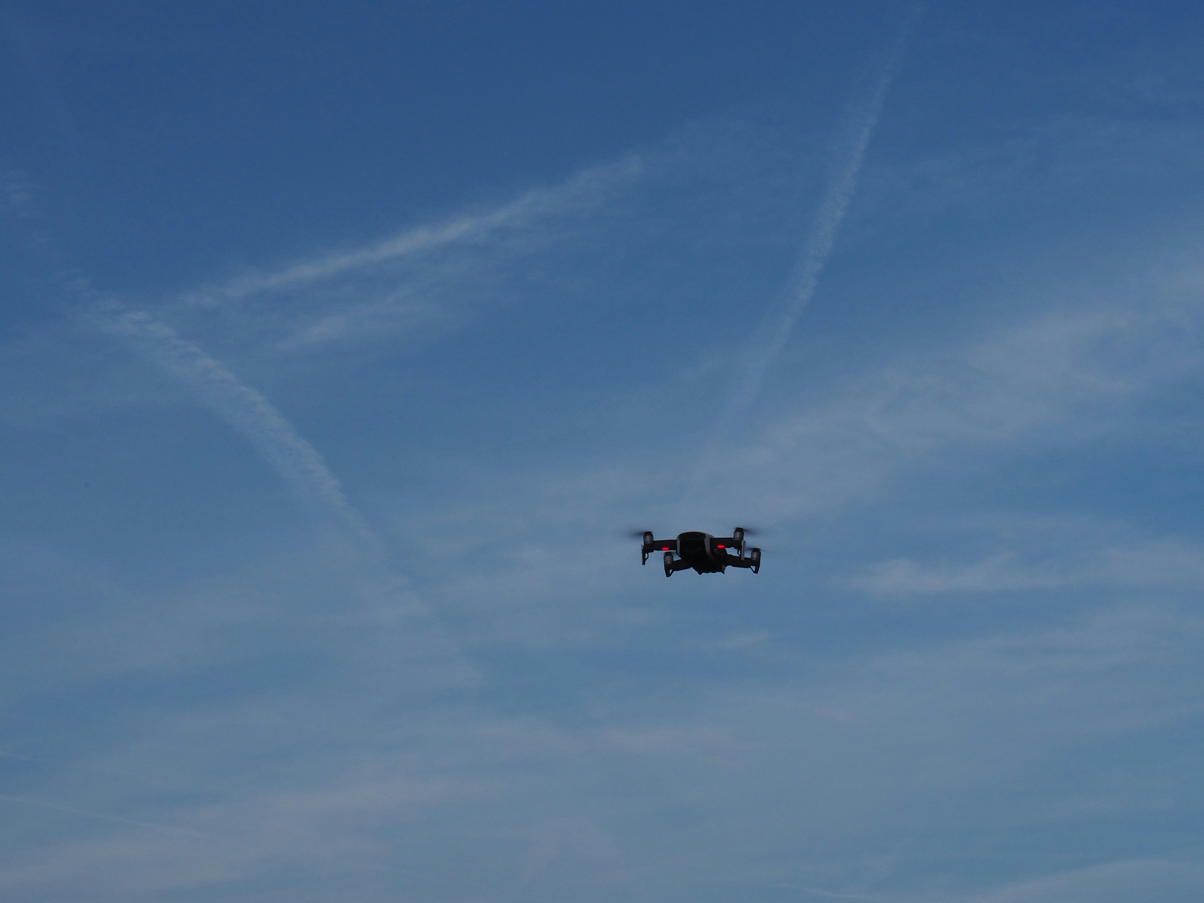 Hovering Speck: A Drone Quietly Traverses a Crisscross Sky