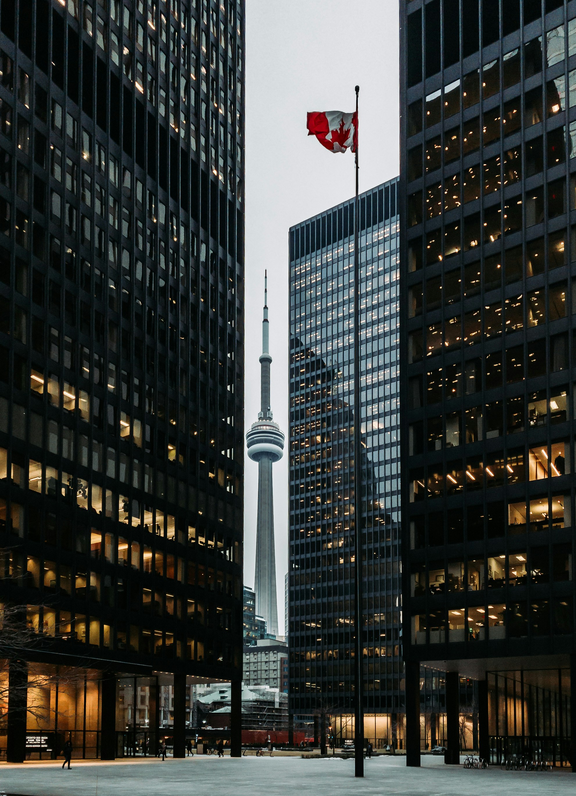 cn tower between buildings and canada flag | black and white high rise buildings