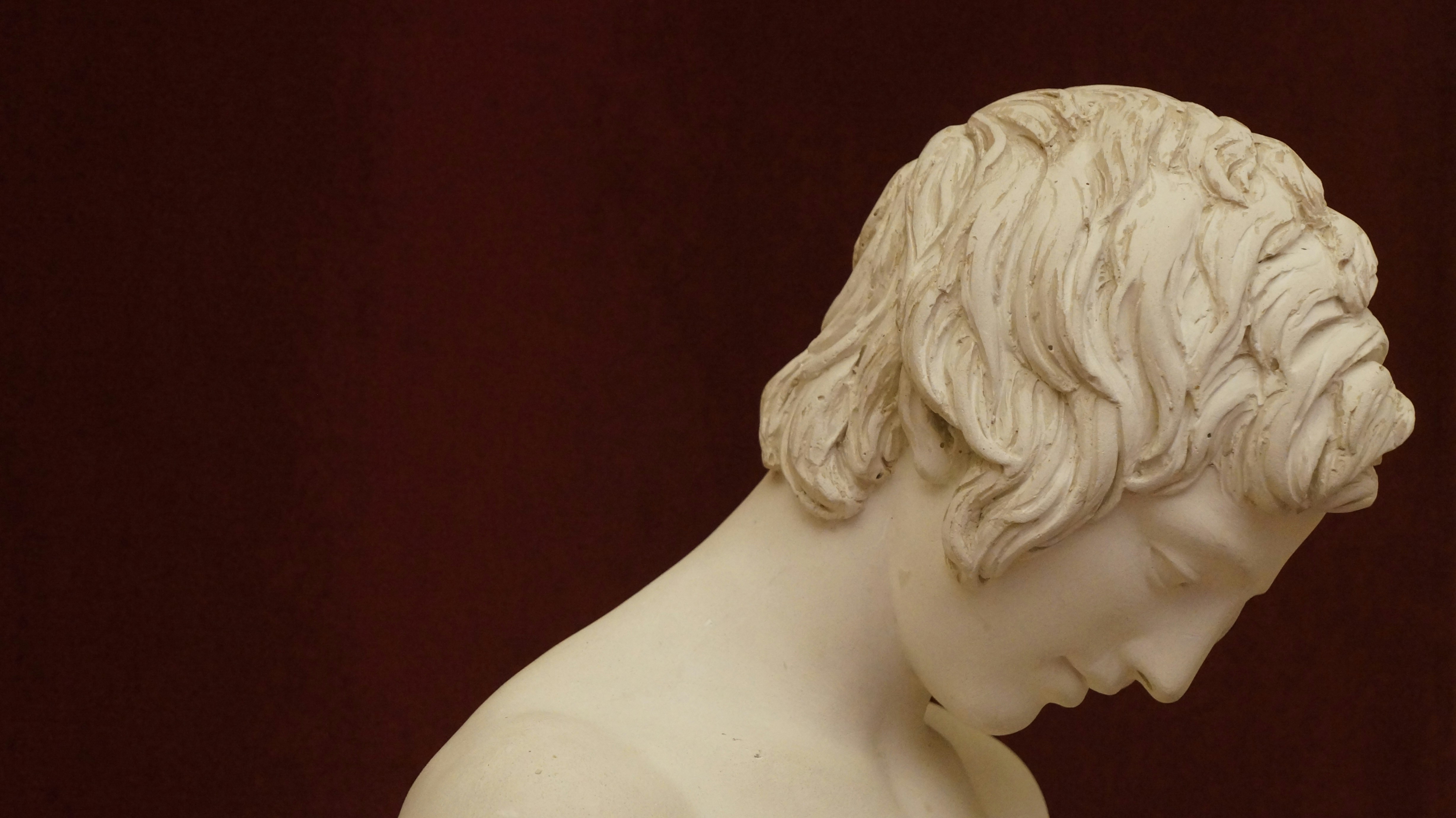 Crimson Backdrop, Marble Quietude: A Bust in Downcast Gaze