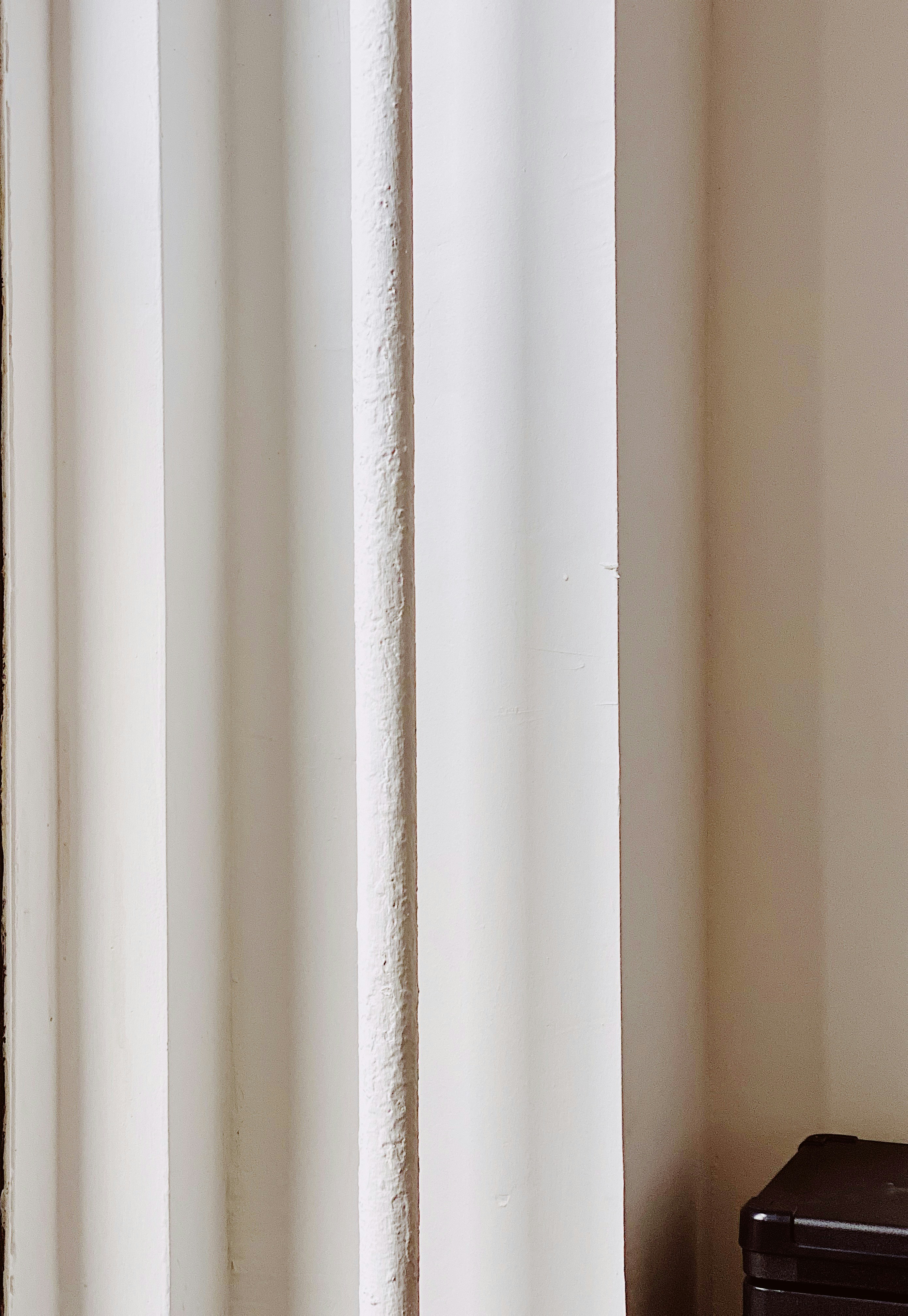 Intricate white columns juxtaposed with a dark wooden element, showcasing a blend of texture and form.