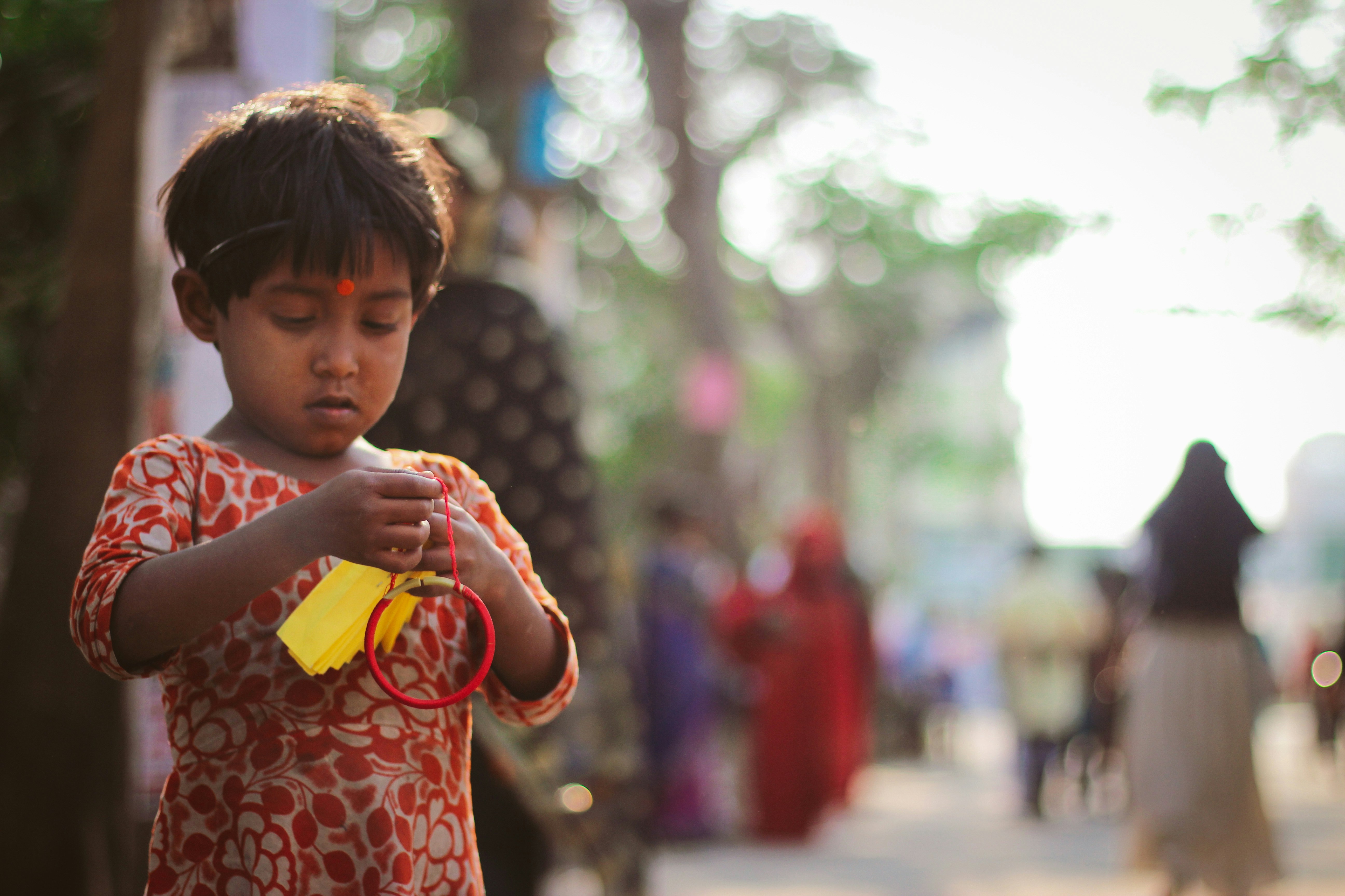 Tiny Toy, Big Moment: A Girl with a Red Flowered Dress Delves into a Yellow Toy