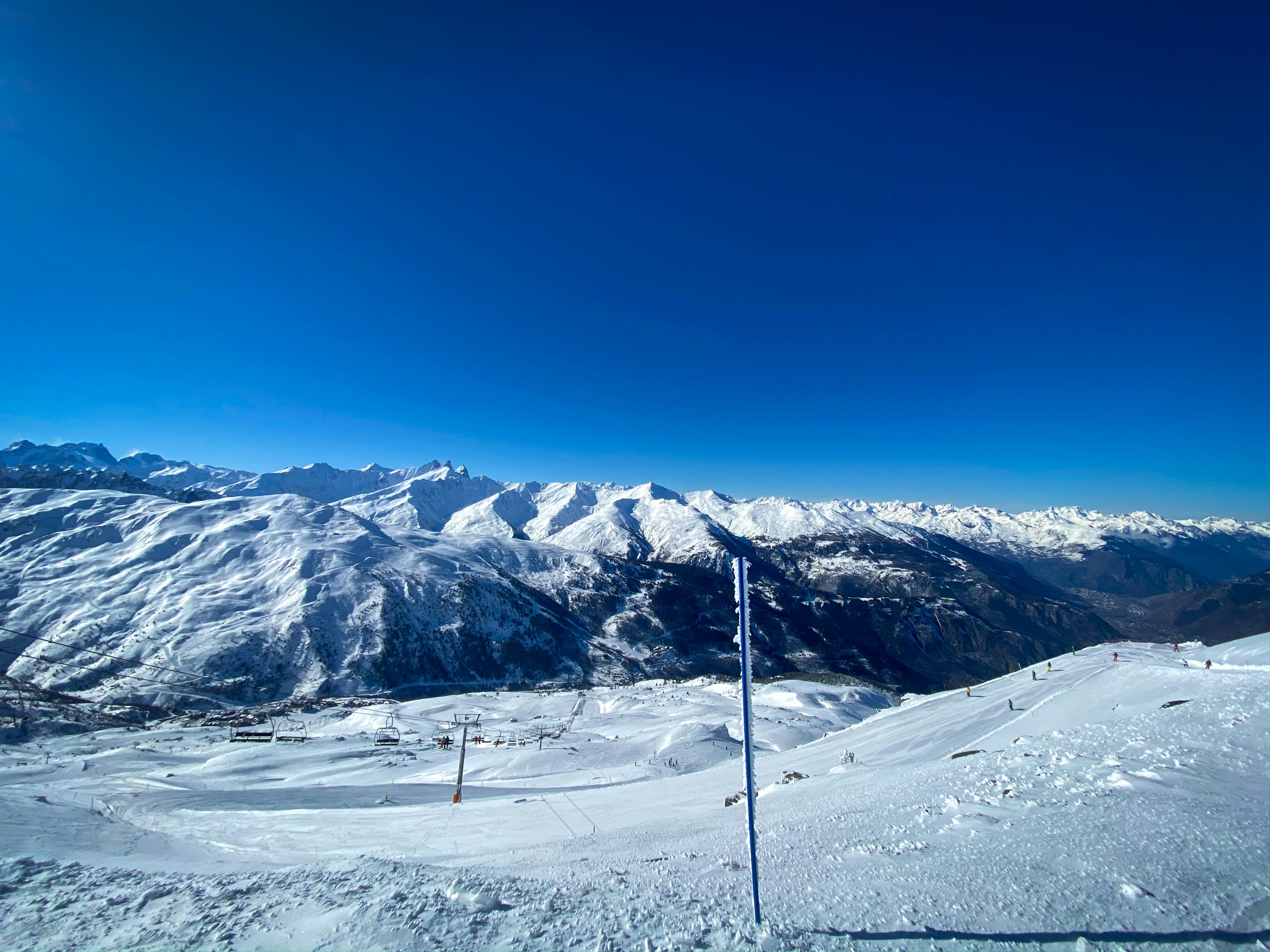 Expansive view of snow-covered mountains under a clear blue sky, showcasing the serene beauty of winter landscapes.