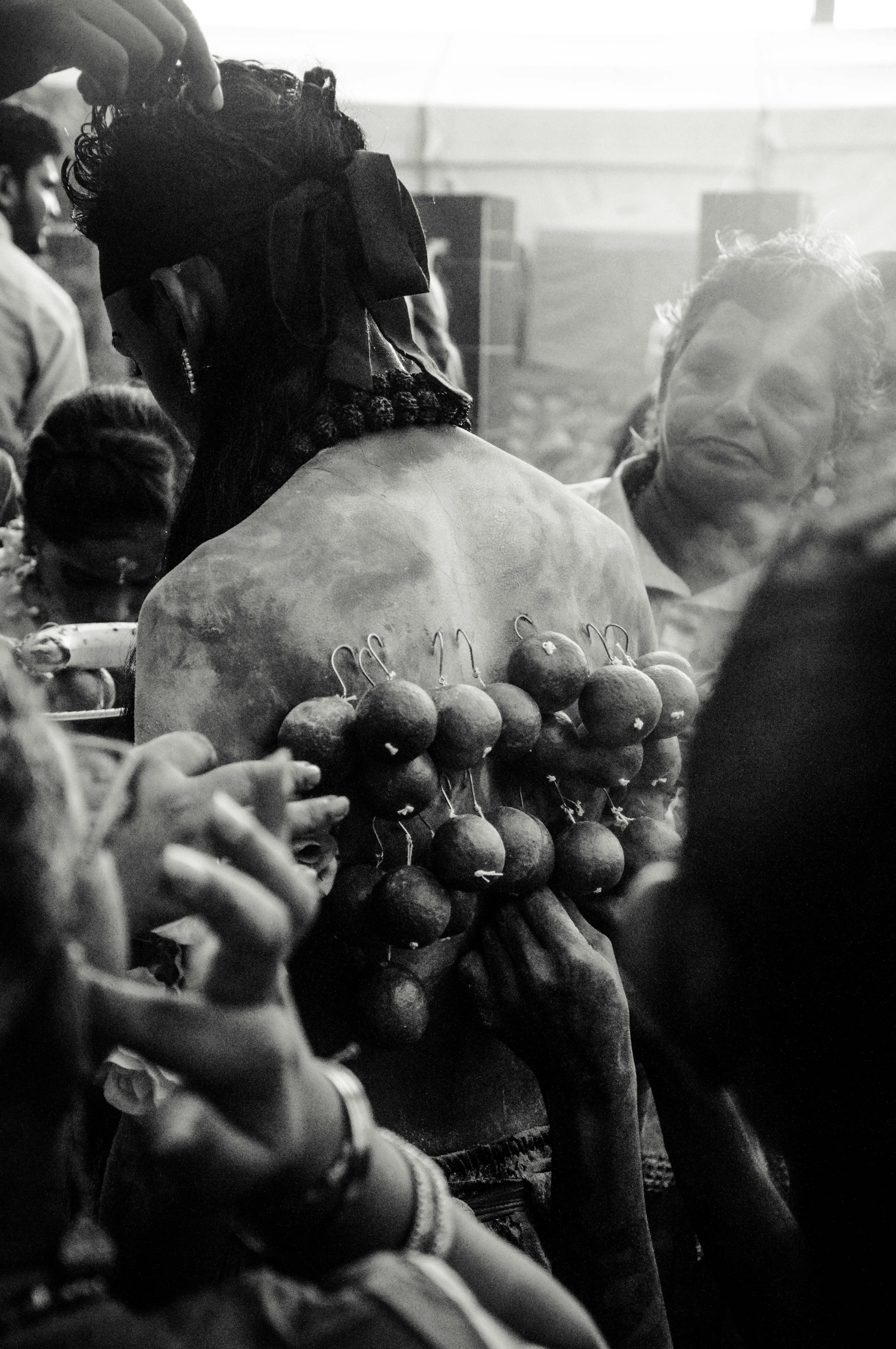 A participant adorned with ritualistic ornaments stands surrounded by onlookers, embodying cultural significance and collective engagement.