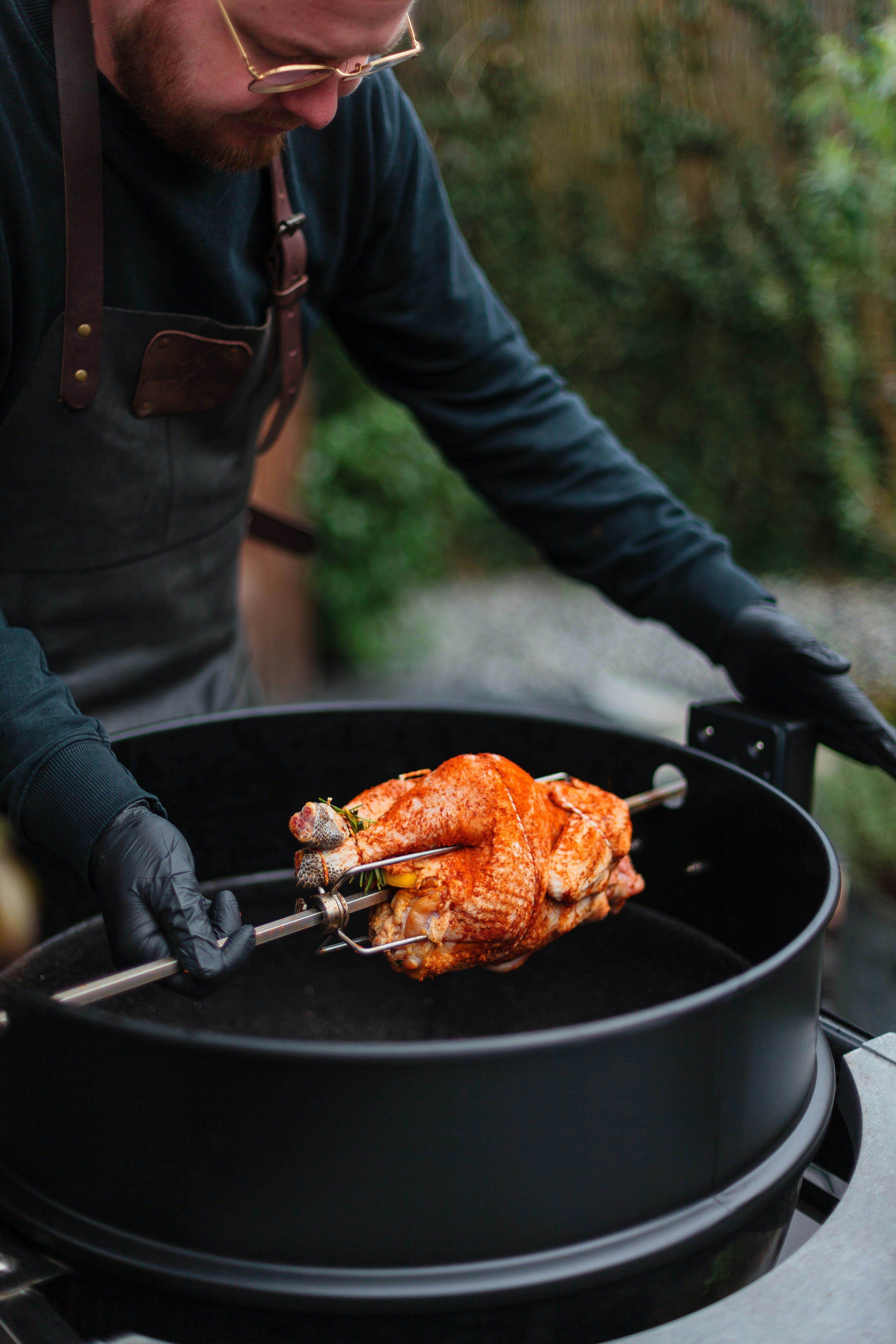 Person in black jacket holding grilled meat on black charcoal grill ...