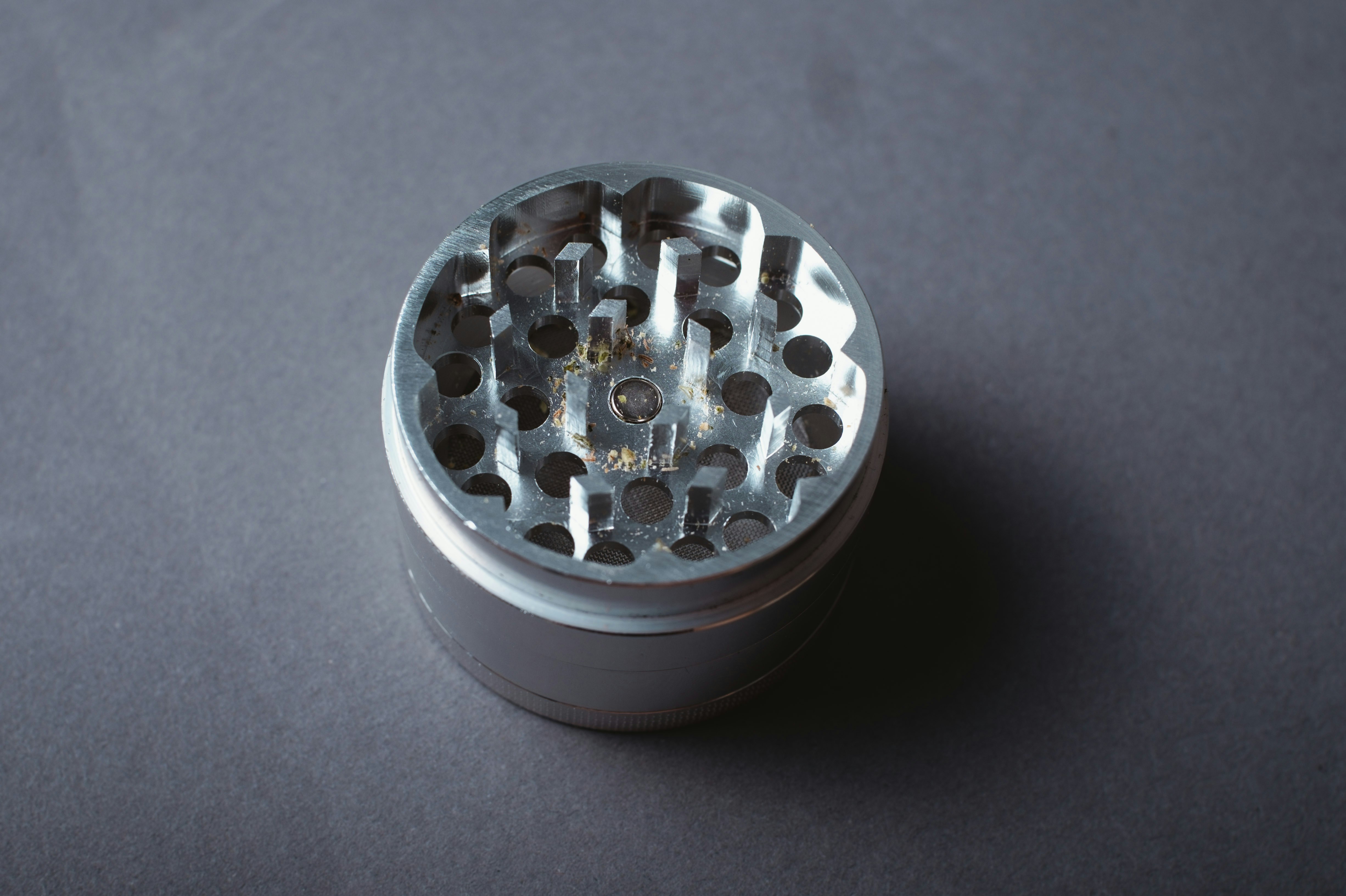 Close-up of a metallic grinder showcasing intricate details and texture against a dark background.