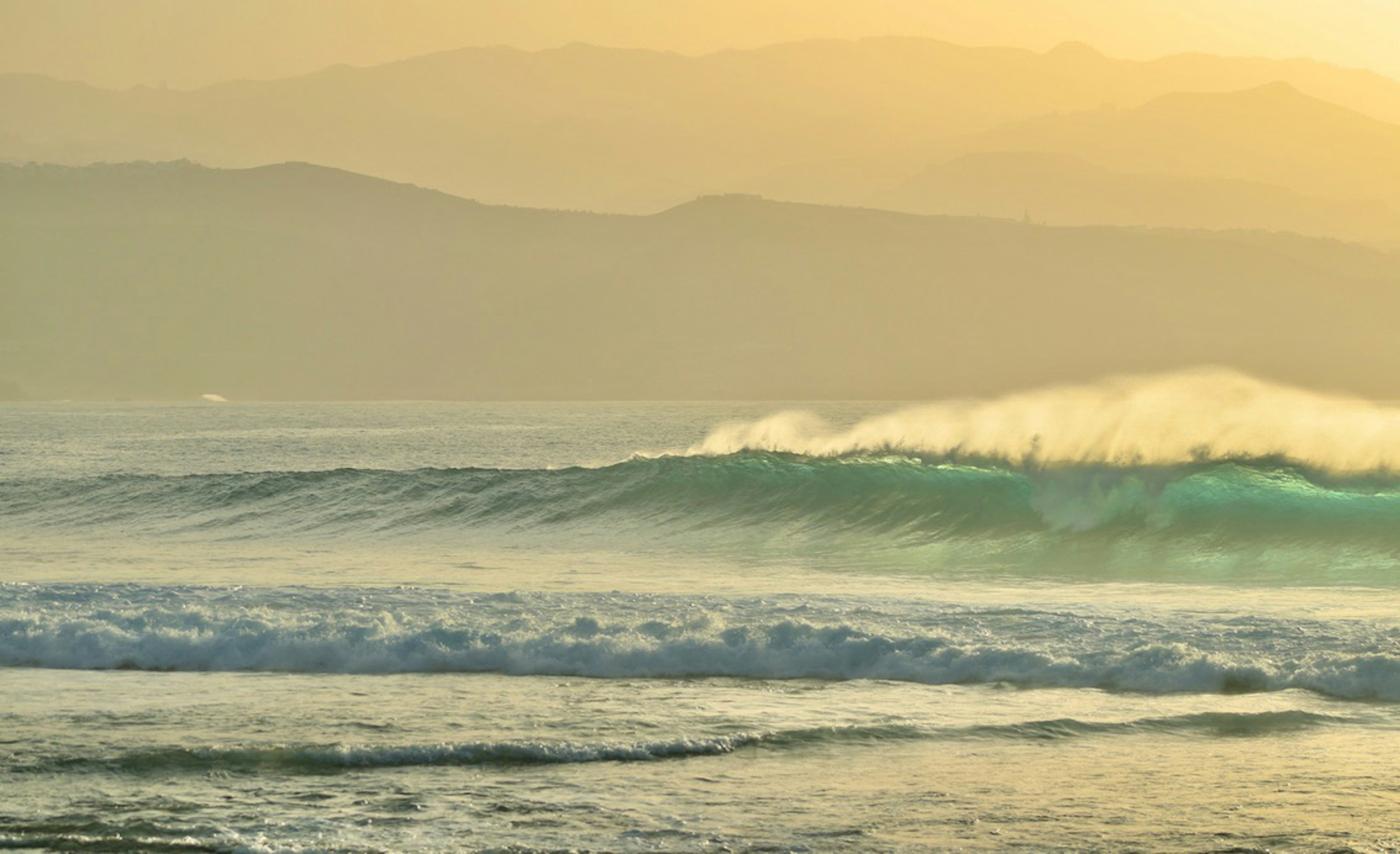Rolling waves illuminated by the golden hues of sunset at Playa El Confital.