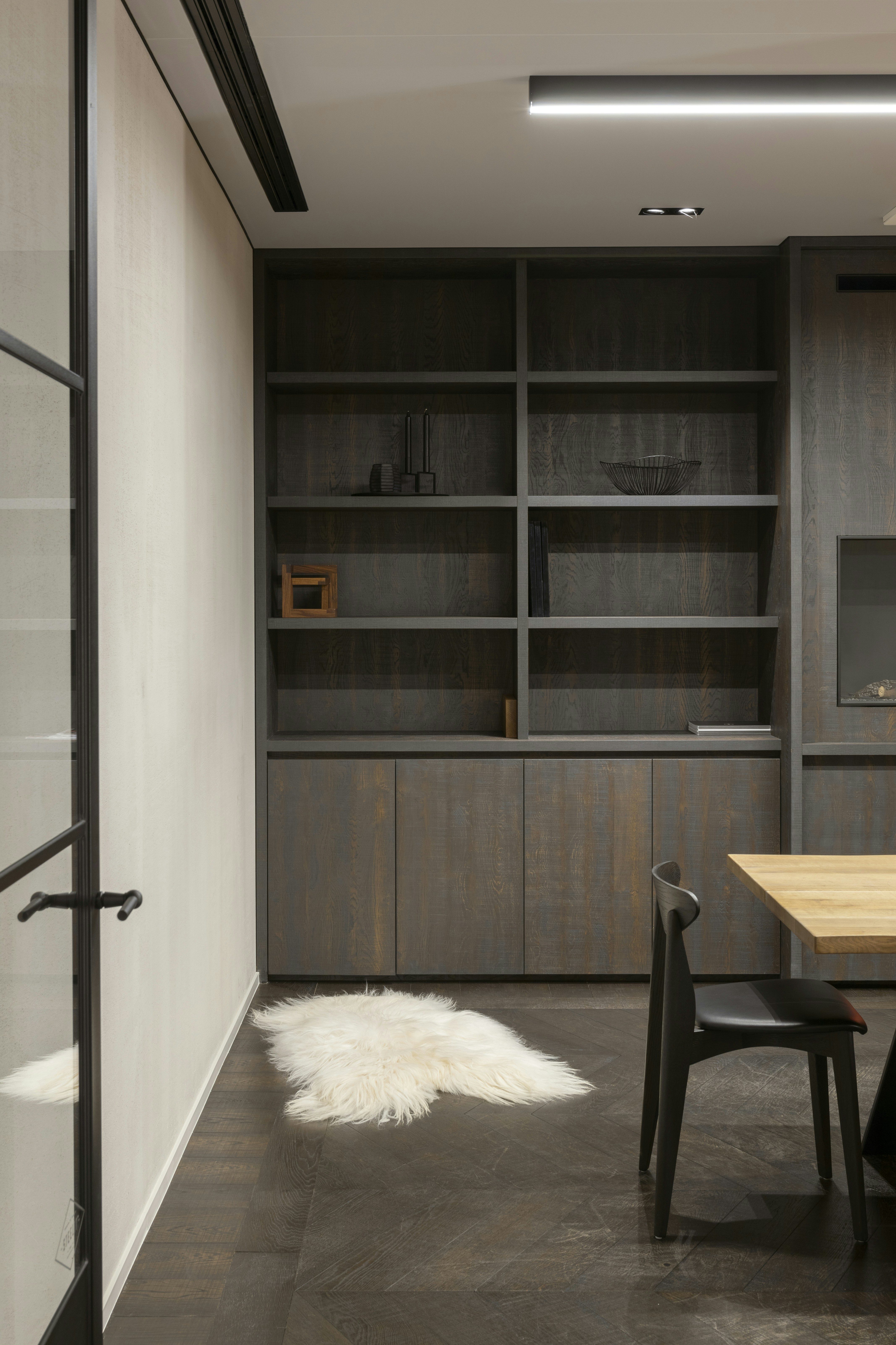 Sleek interior featuring dark wooden shelves and a minimalist dining table, complemented by a soft white rug on the floor.