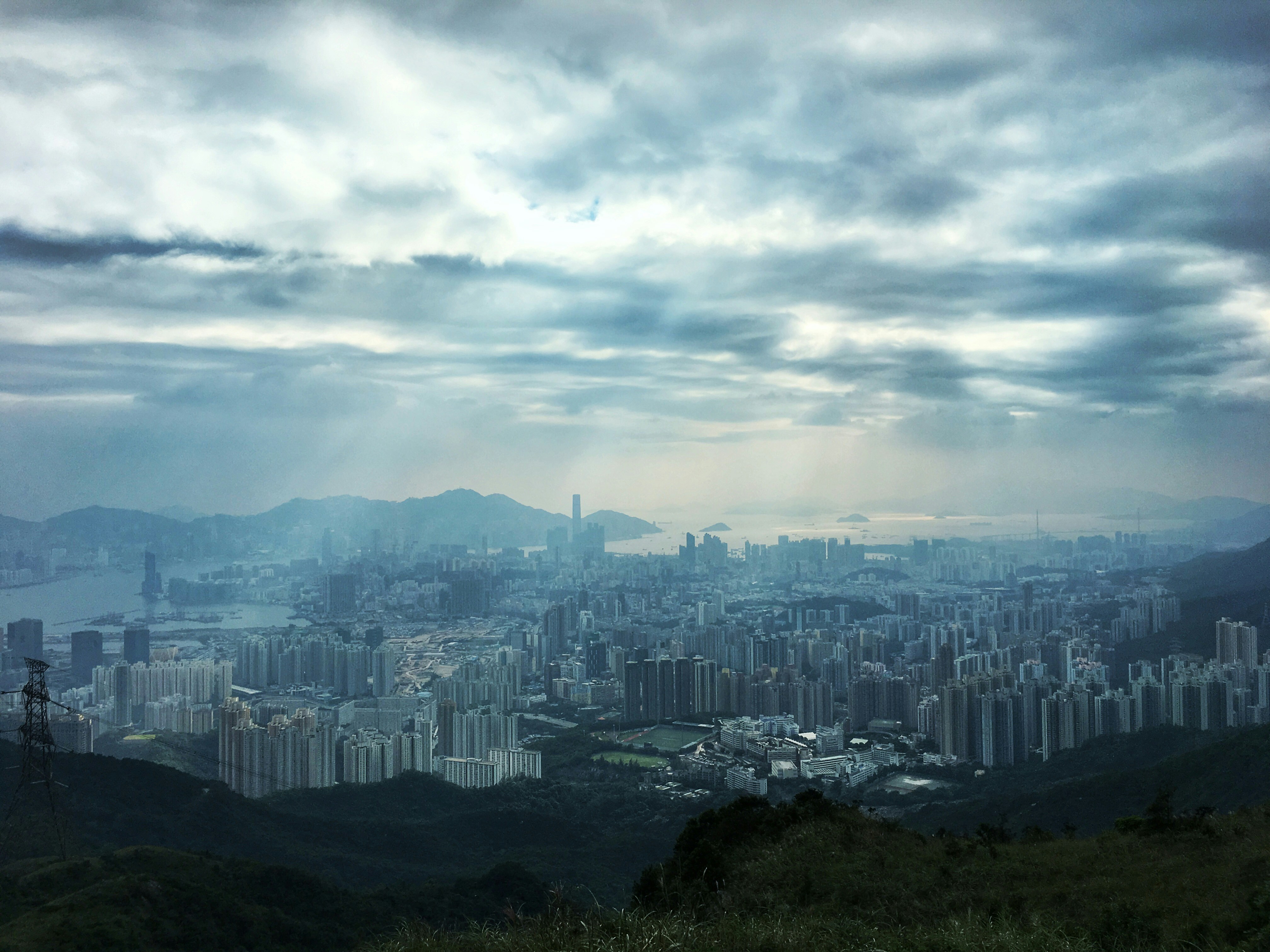 Expansive view of a sprawling cityscape under a dramatic sky, showcasing a blend of urban architecture and natural terrain.