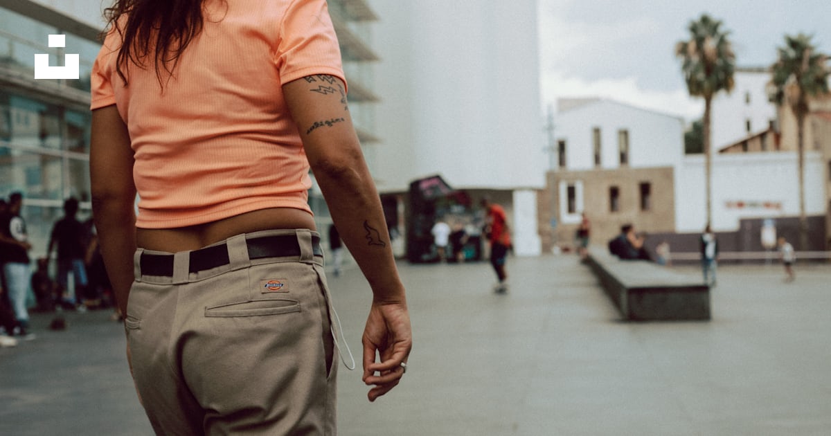 Mujer Con Camiseta Naranja Y Pantalones Grises Caminando Por La Acera