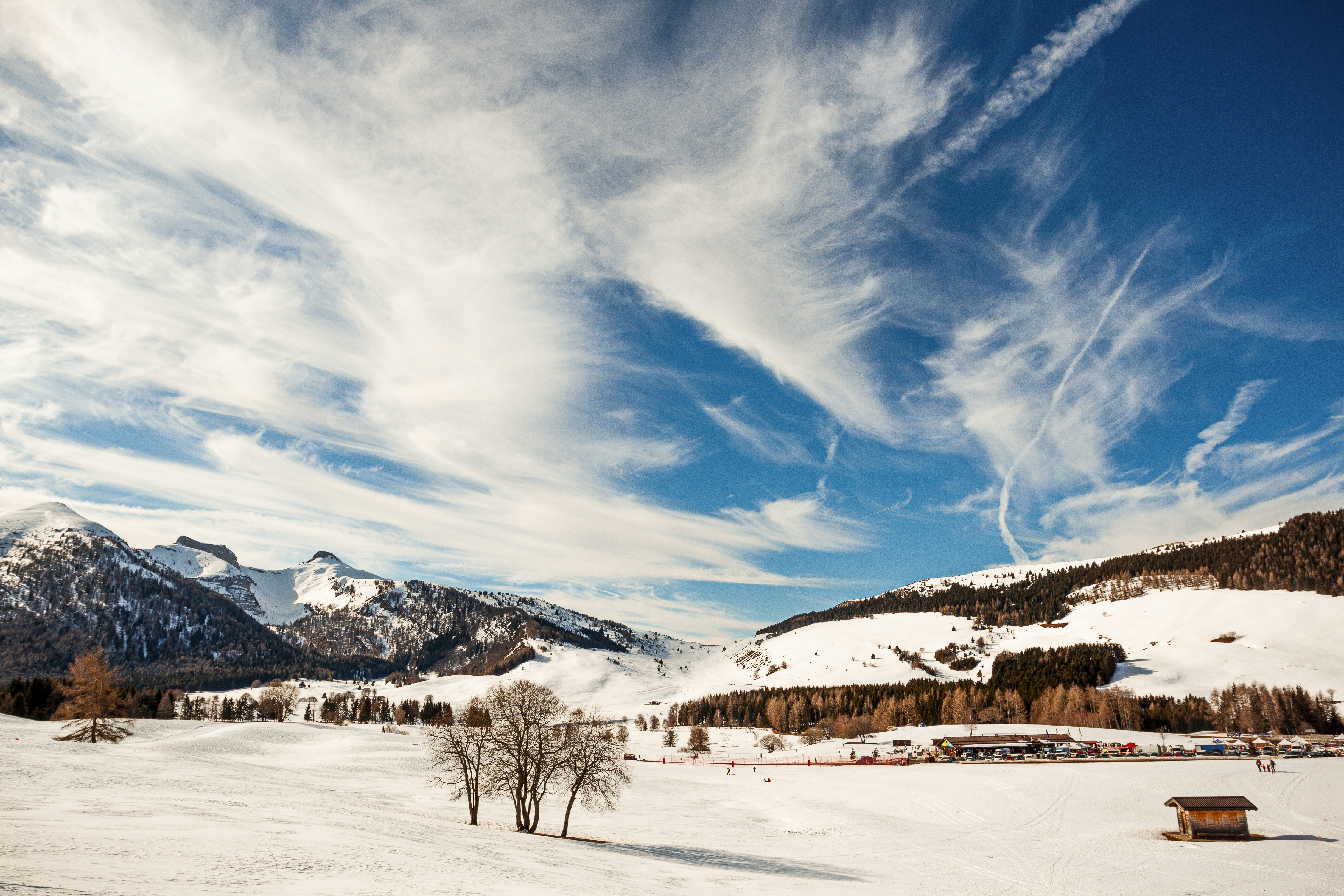 Snow-covered landscape with distant mountains and dramatic cloud formations in a vivid blue sky.