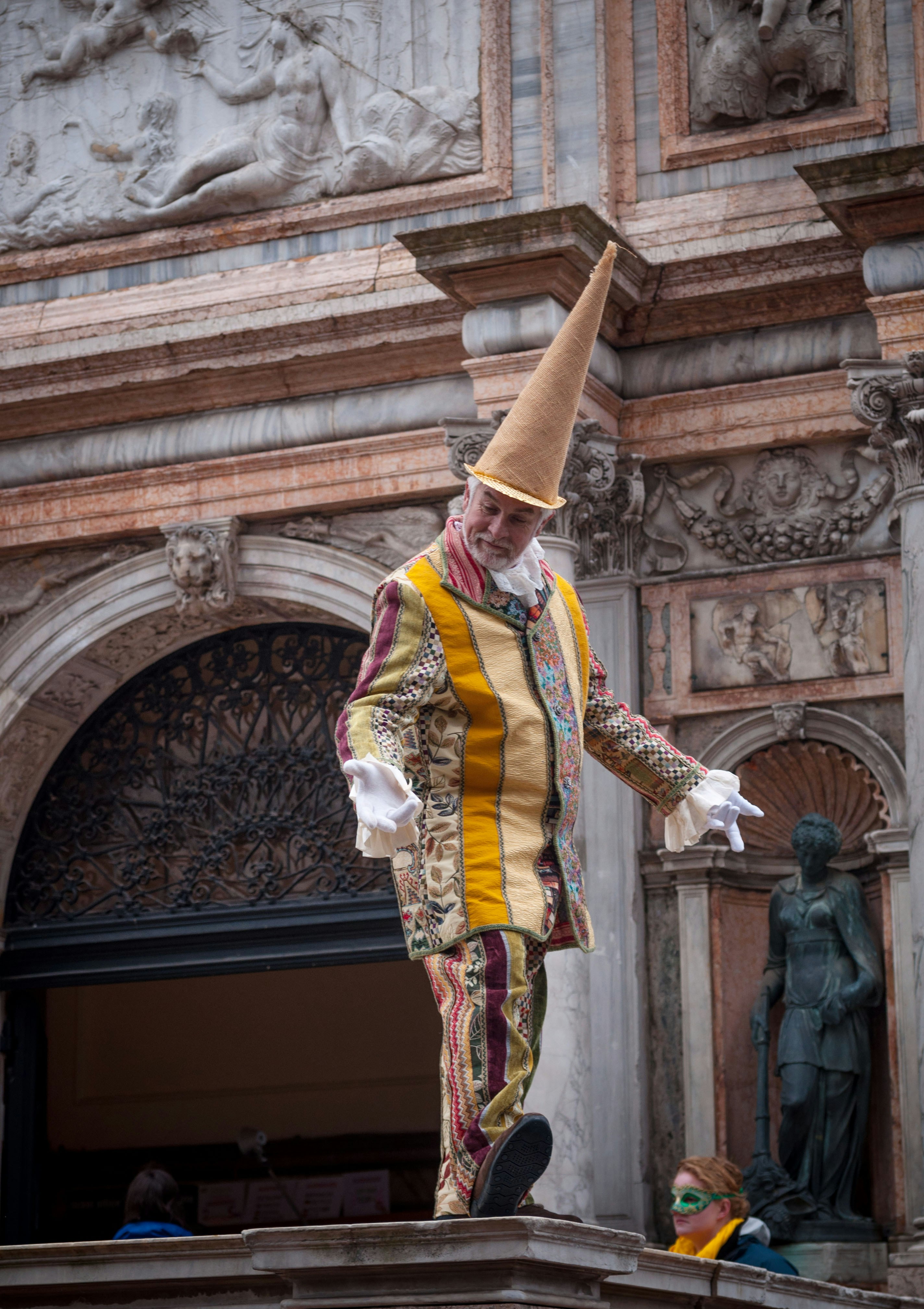 Patchwork Clown on Marble Pedestal Before Baroque Facades