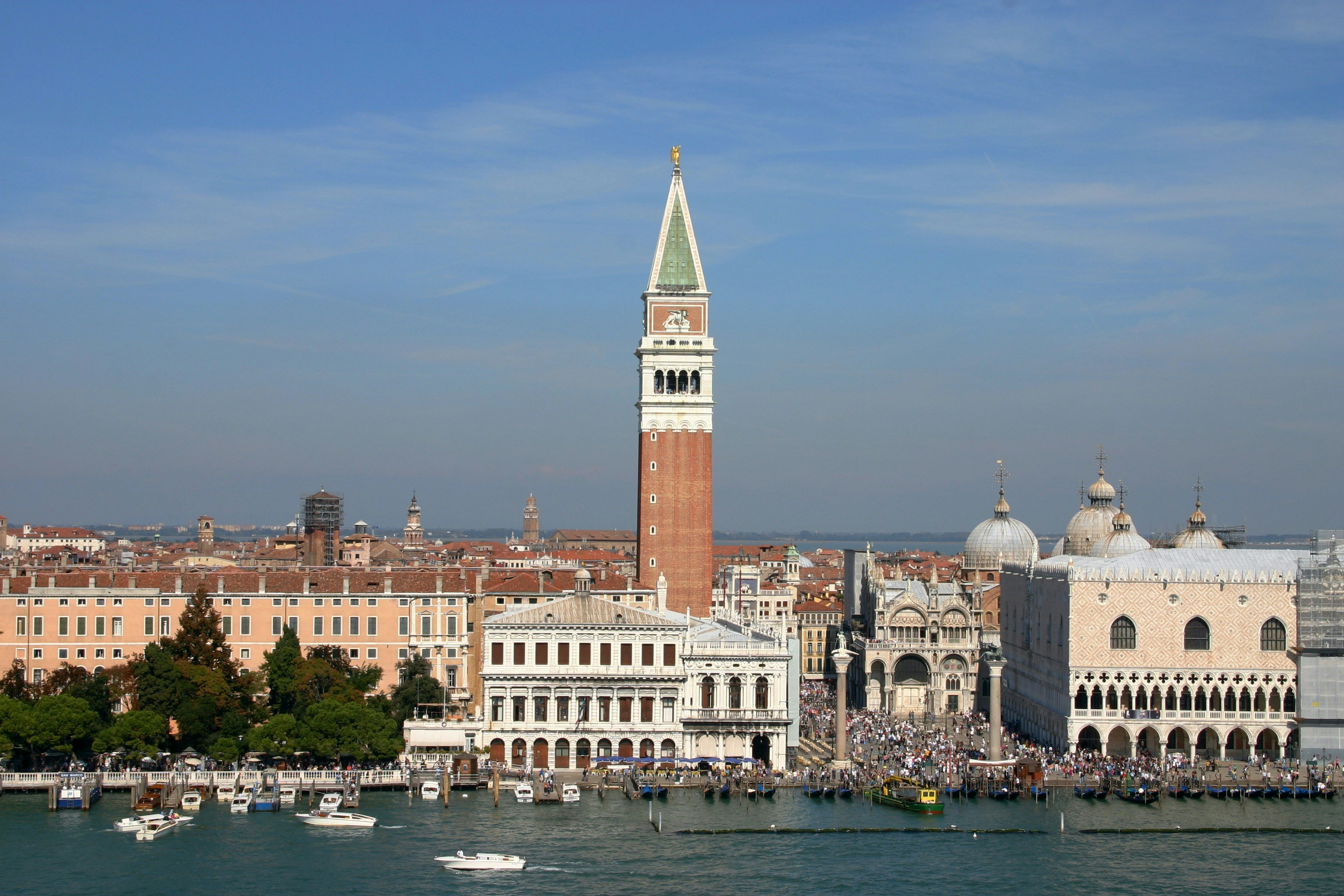 Venetian skyline featuring the iconic Campanile di San Marco and historic buildings along the waterfront. A vibrant scene bustling with visitors.