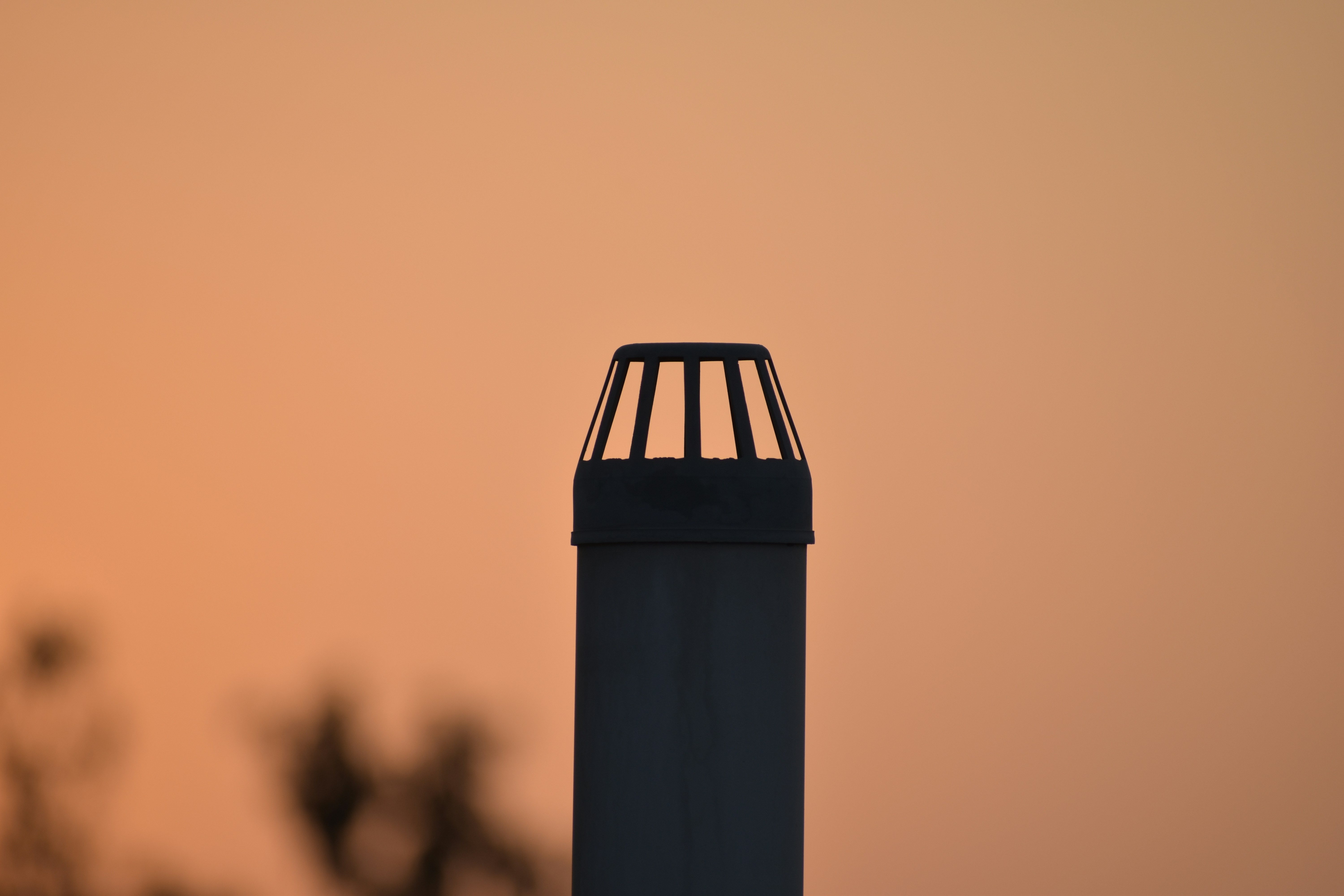 Sunset Silhouette: A Chimney Crown Against a Peach Sky