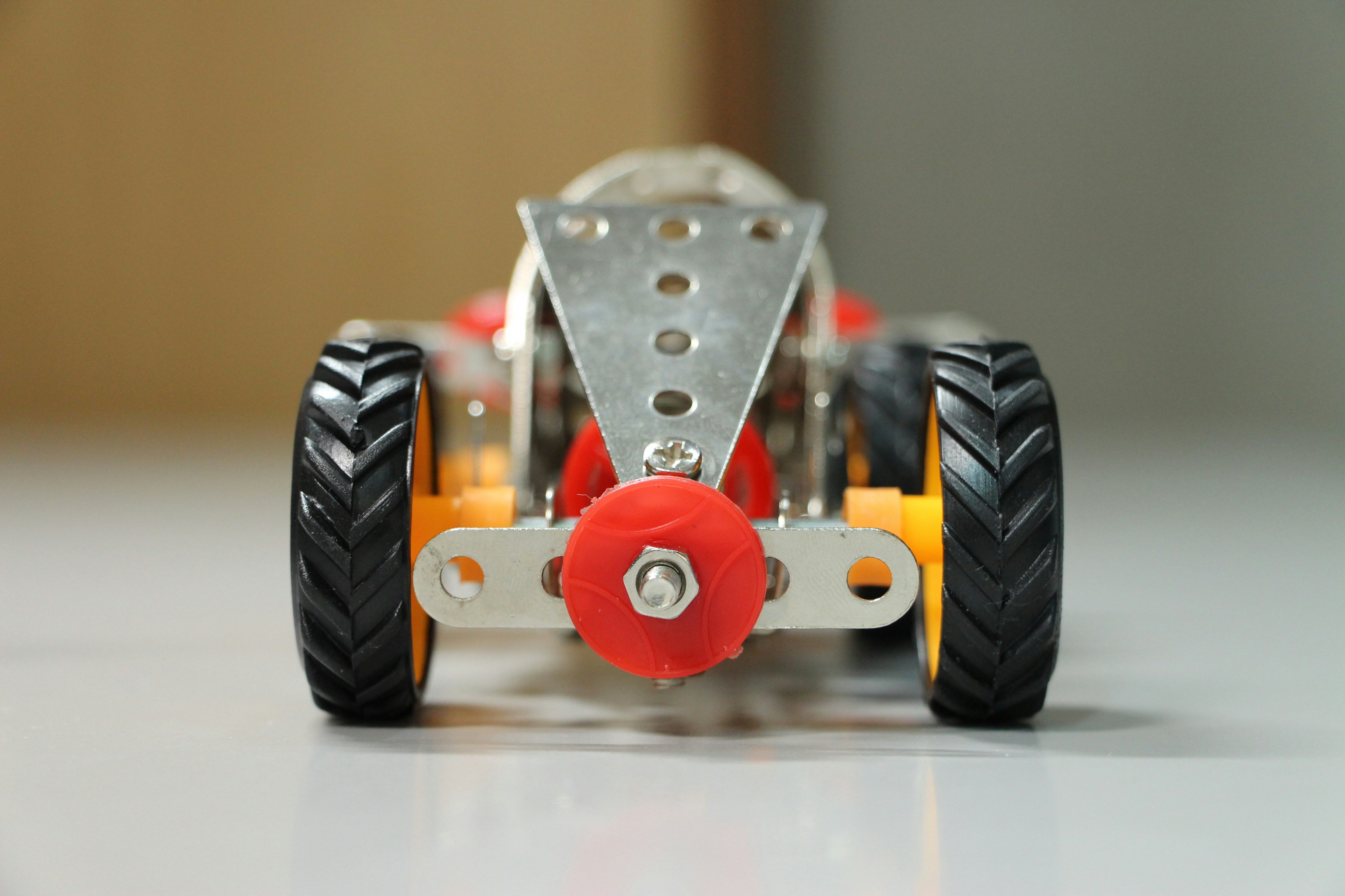 Front-facing toy car chassis centered with red drivetrain knob