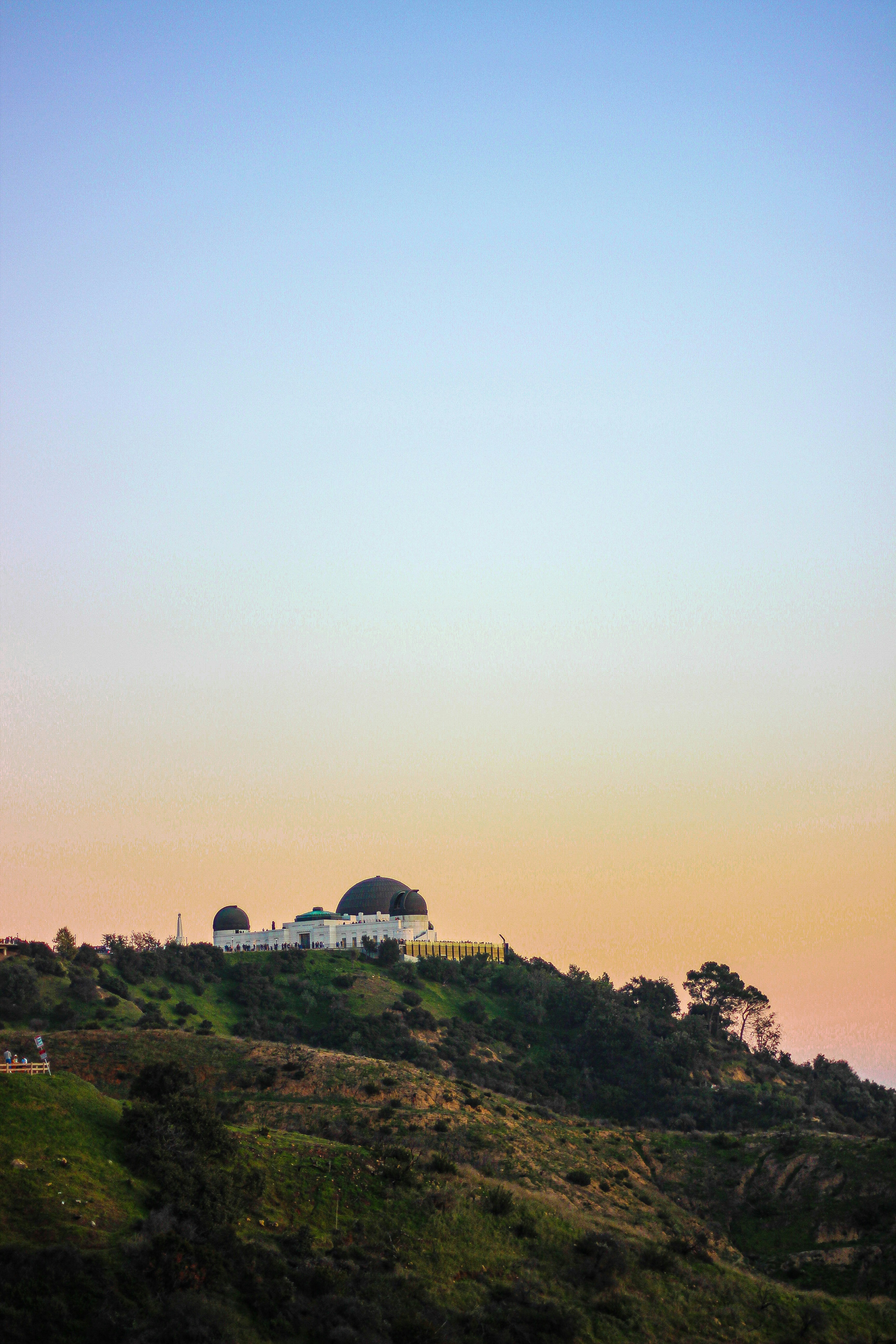 A prominent observatory perched on a hillside, silhouetted against a gradient sky transitioning from soft blue to warm orange hues.
