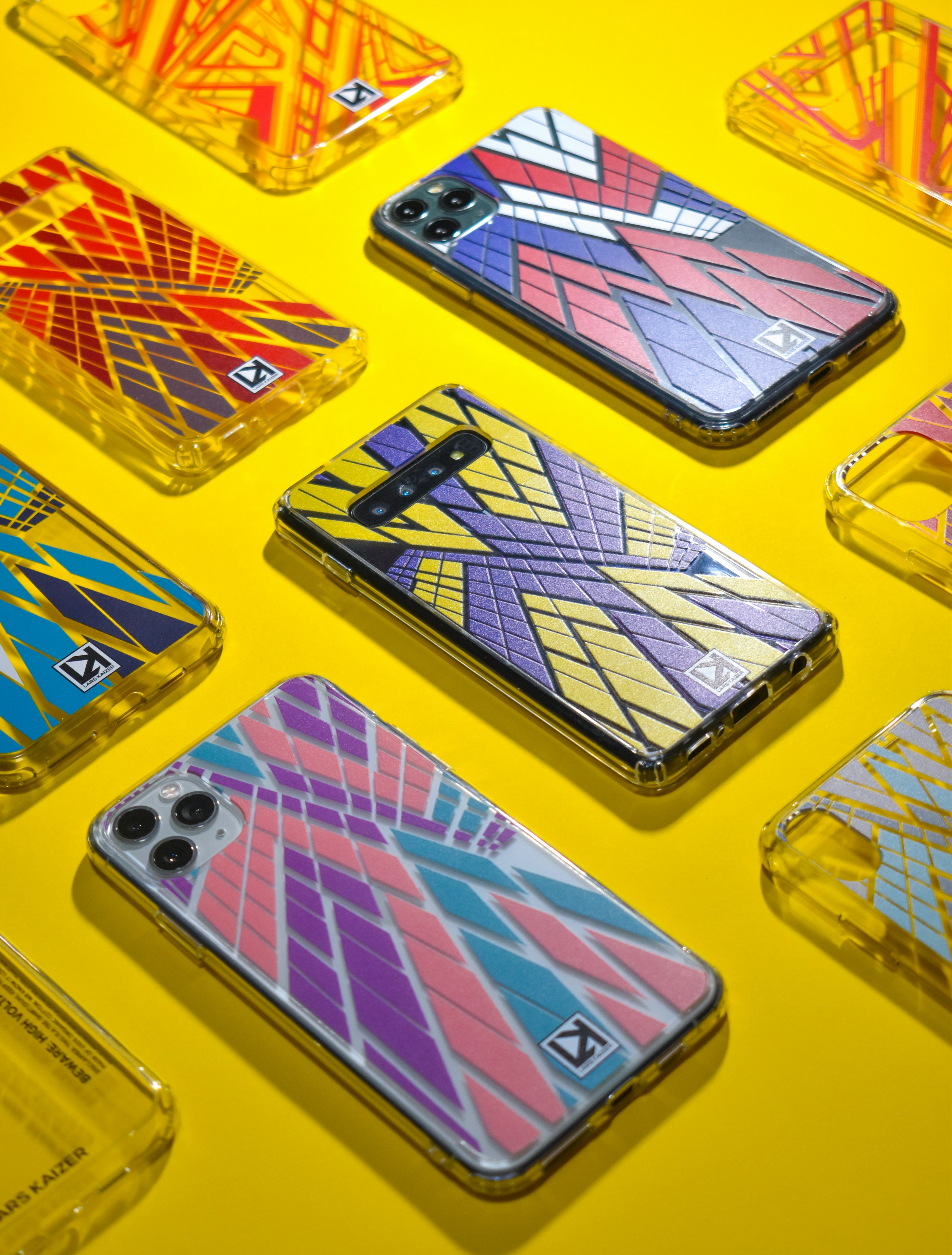 Colorful smartphone cases arranged artistically on a bright yellow background, showcasing intricate geometric patterns.
