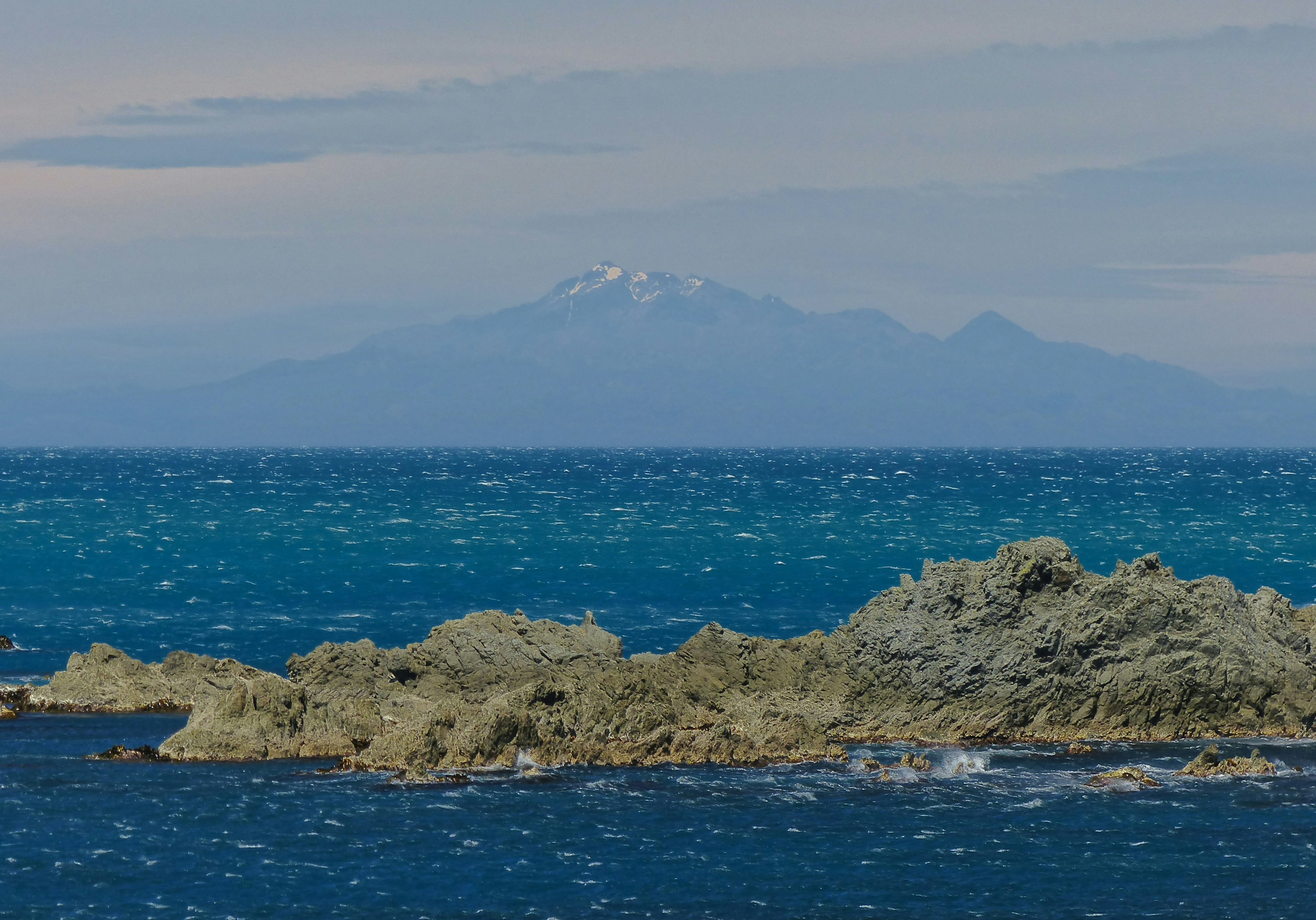 Brown and green rock formation on blue sea under blue sky during ...