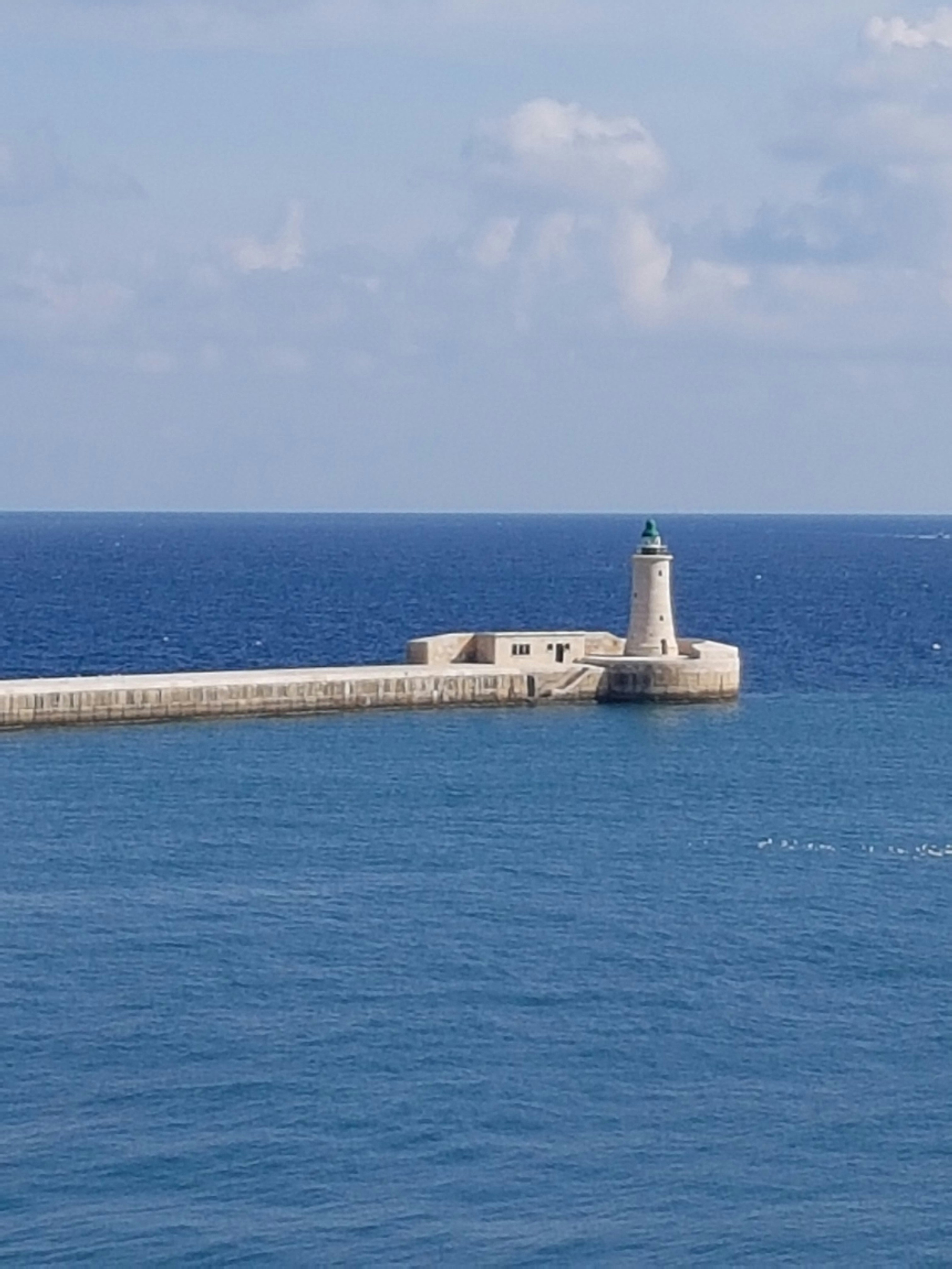 White concrete building on sea under blue sky during daytime photo ...