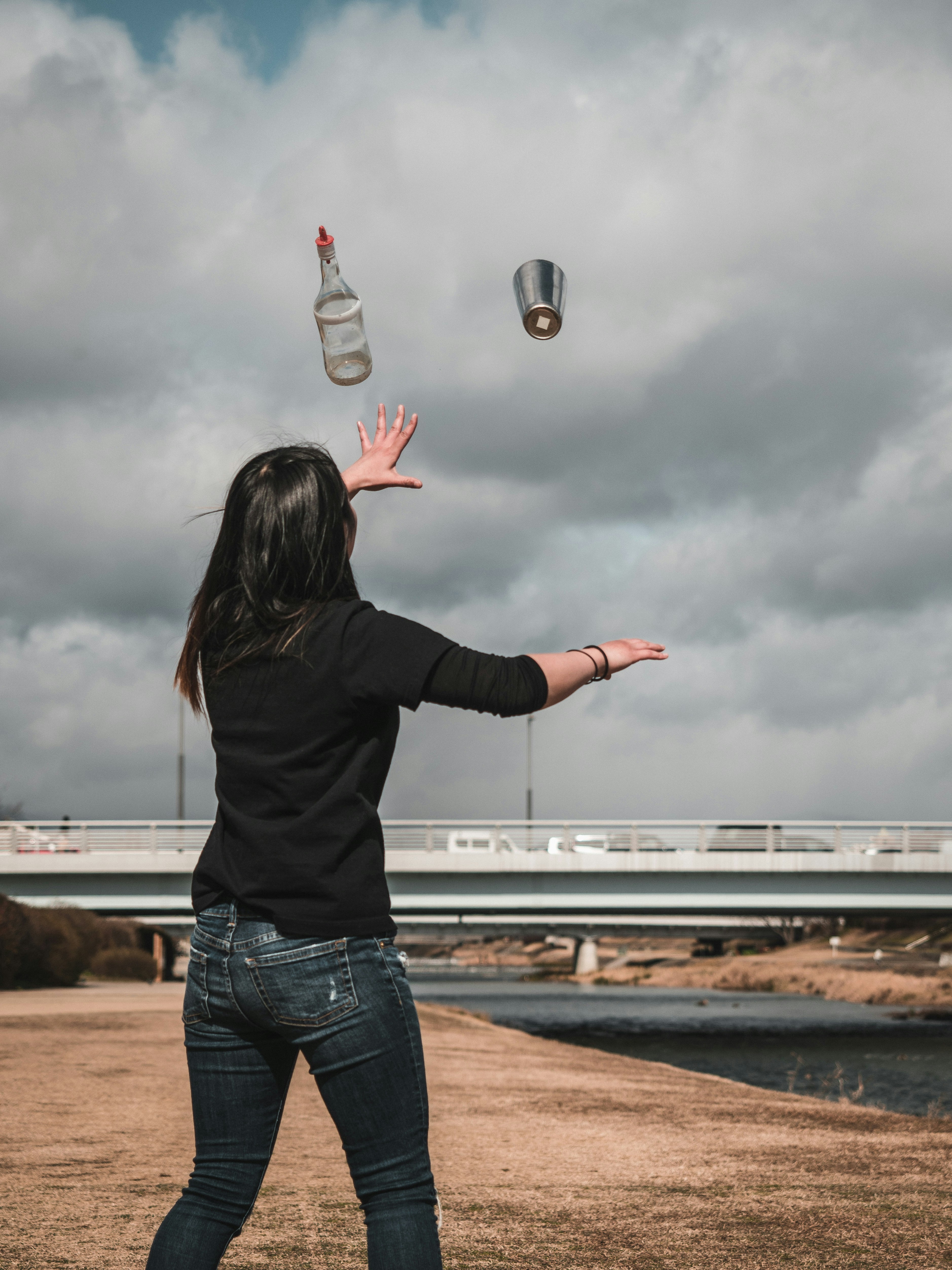 Woman in black long sleeve shirt and blue denim jeans holding clear ...