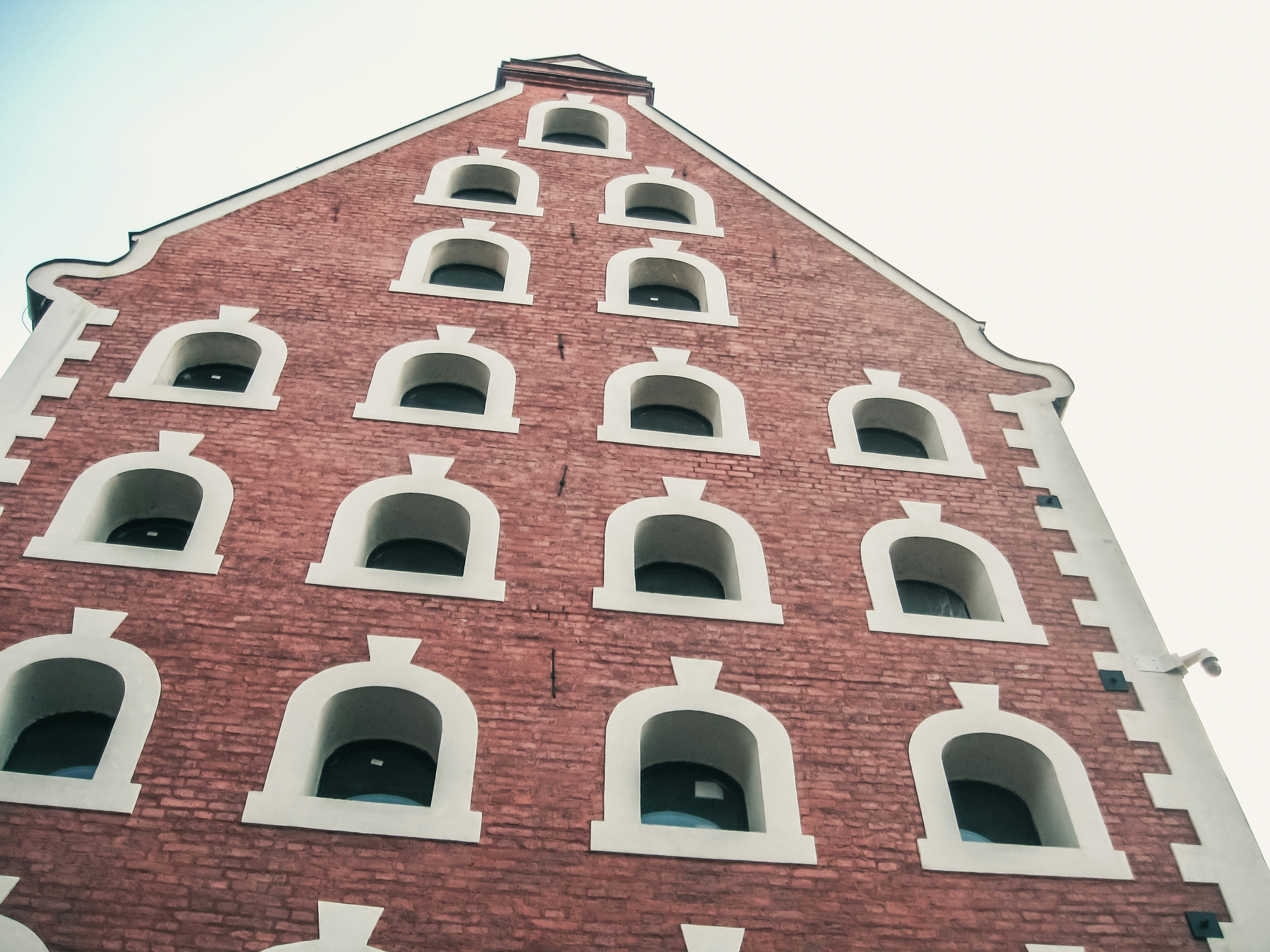 Red brick building with multiple symmetrical white-trimmed windows against a pale sky.
