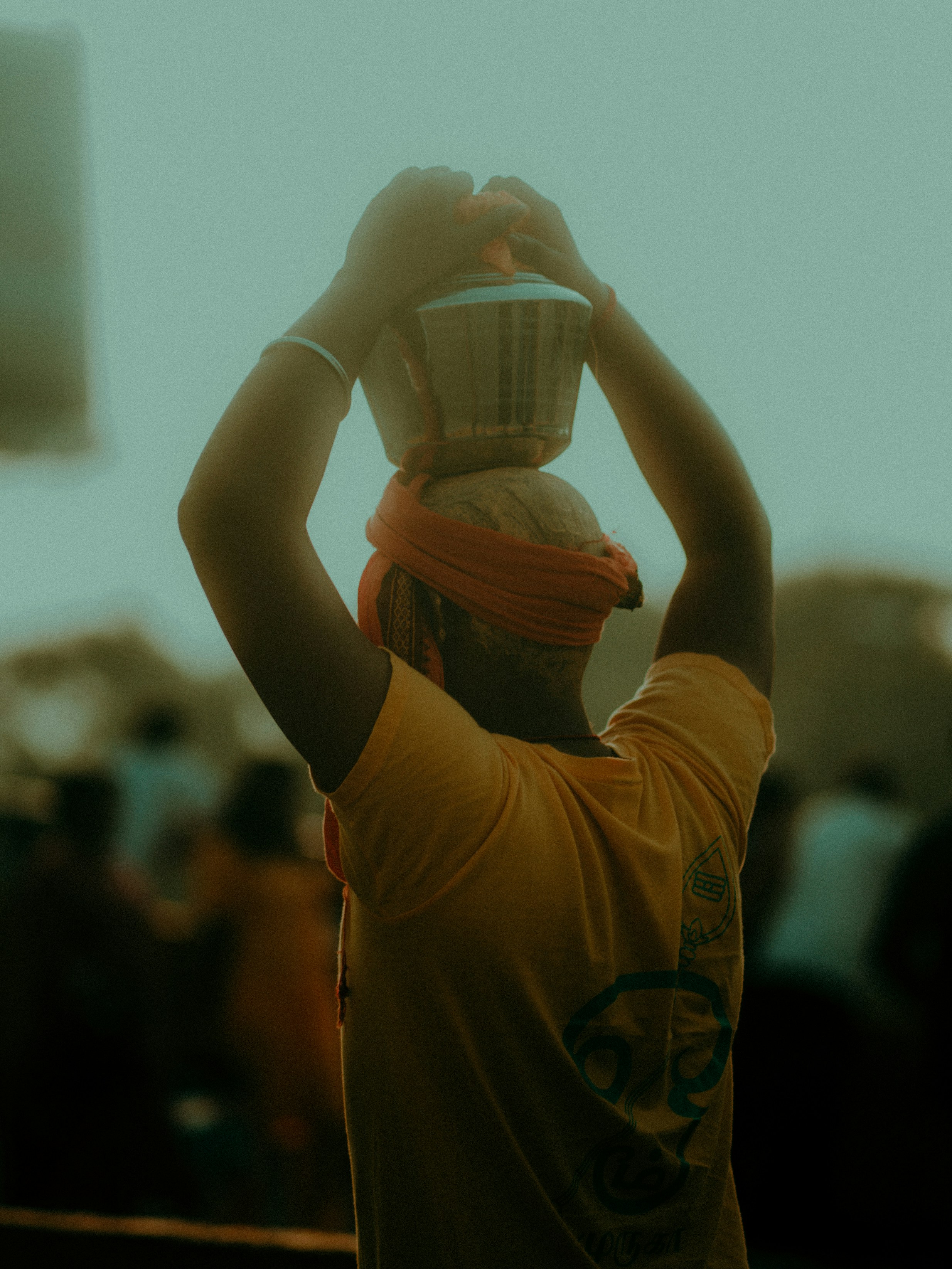 Balancing a Metal Vessel on the Head in a Hazy Street Crowd
