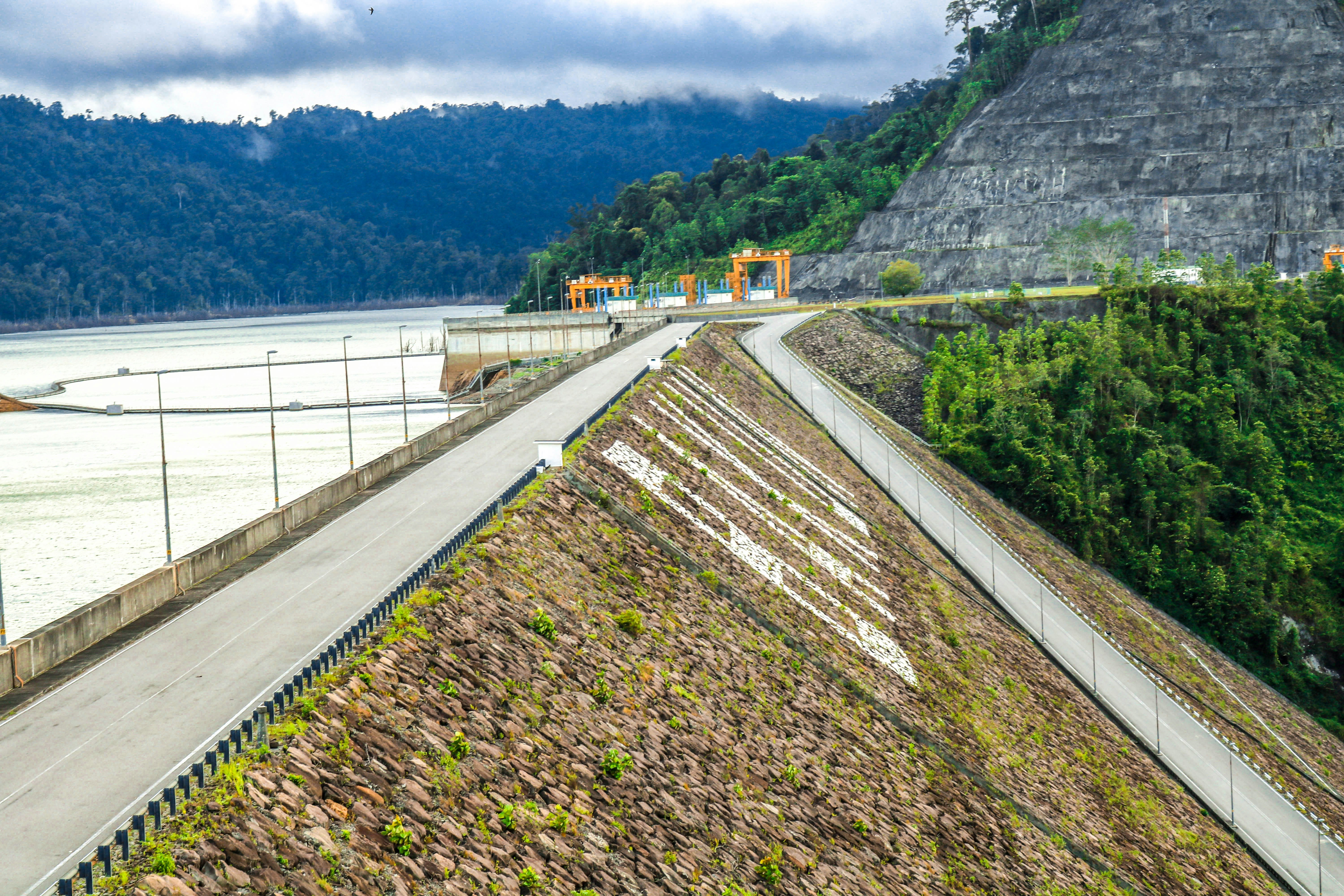 Crest of the Dam: Road Toward the Distant Yellow Gantries