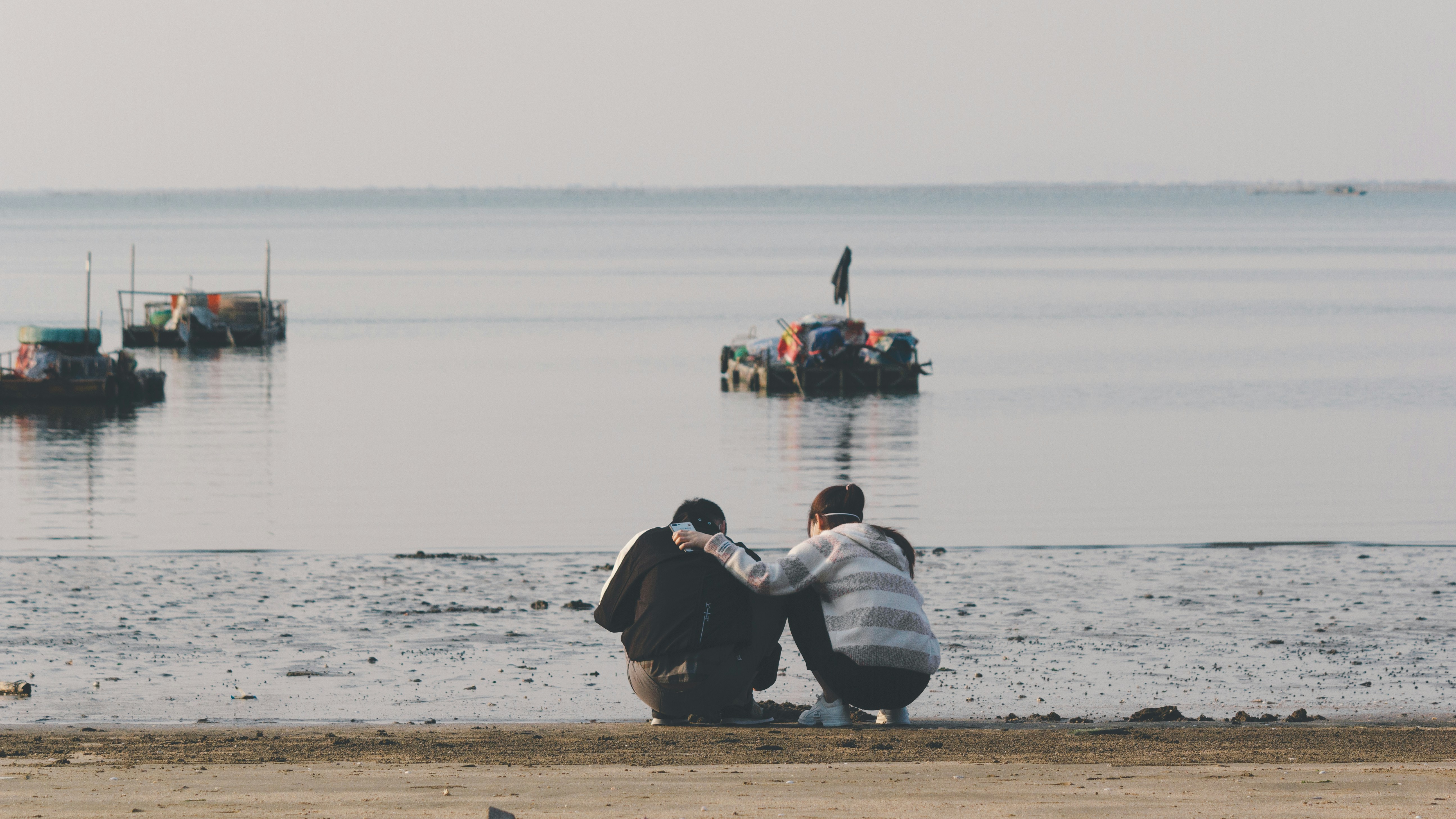 2 men sitting on beach shore during daytime photo – Free Human Image on ...