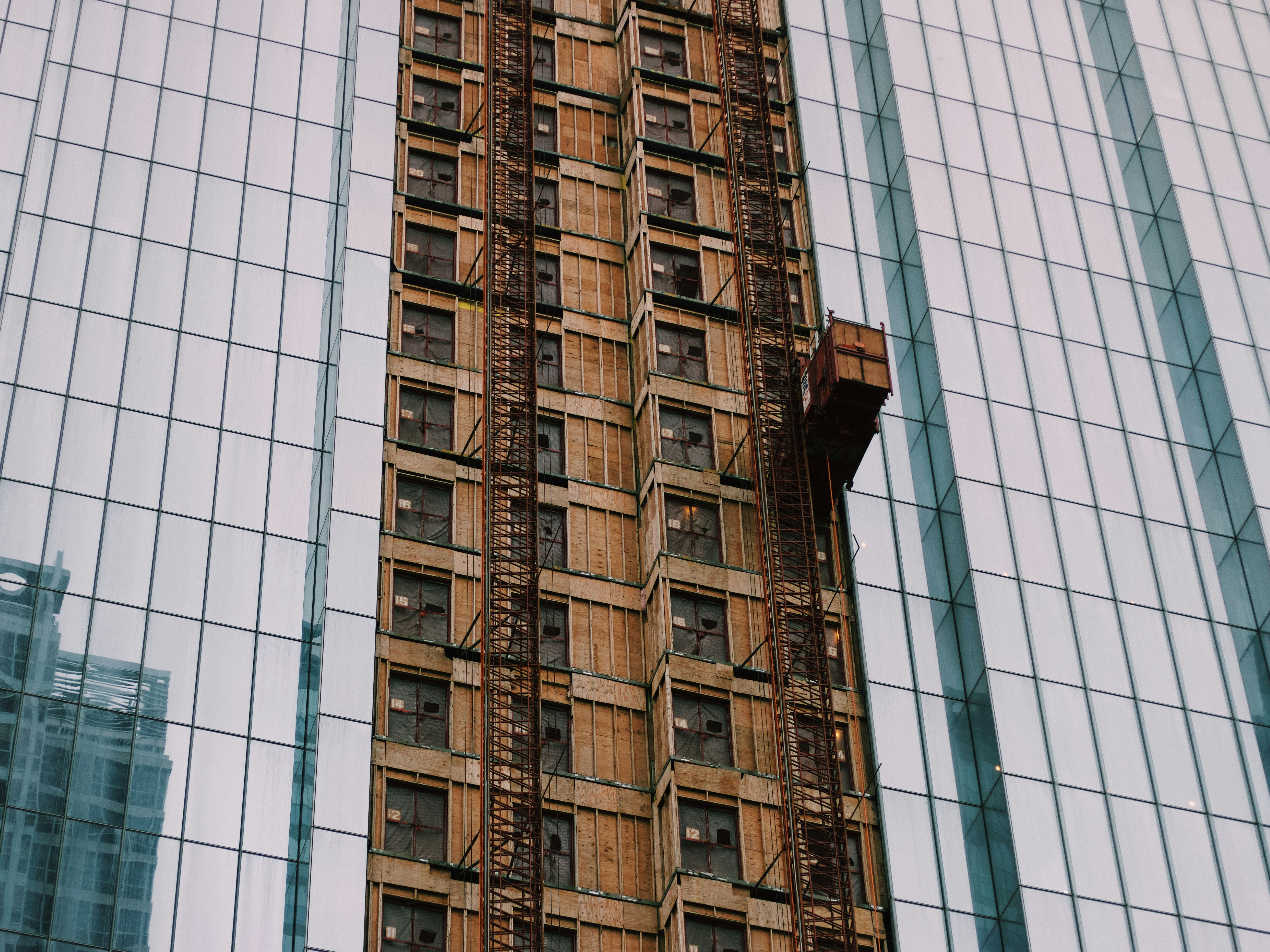 Construction scaffolding juxtaposed against sleek glass buildings in an urban environment.