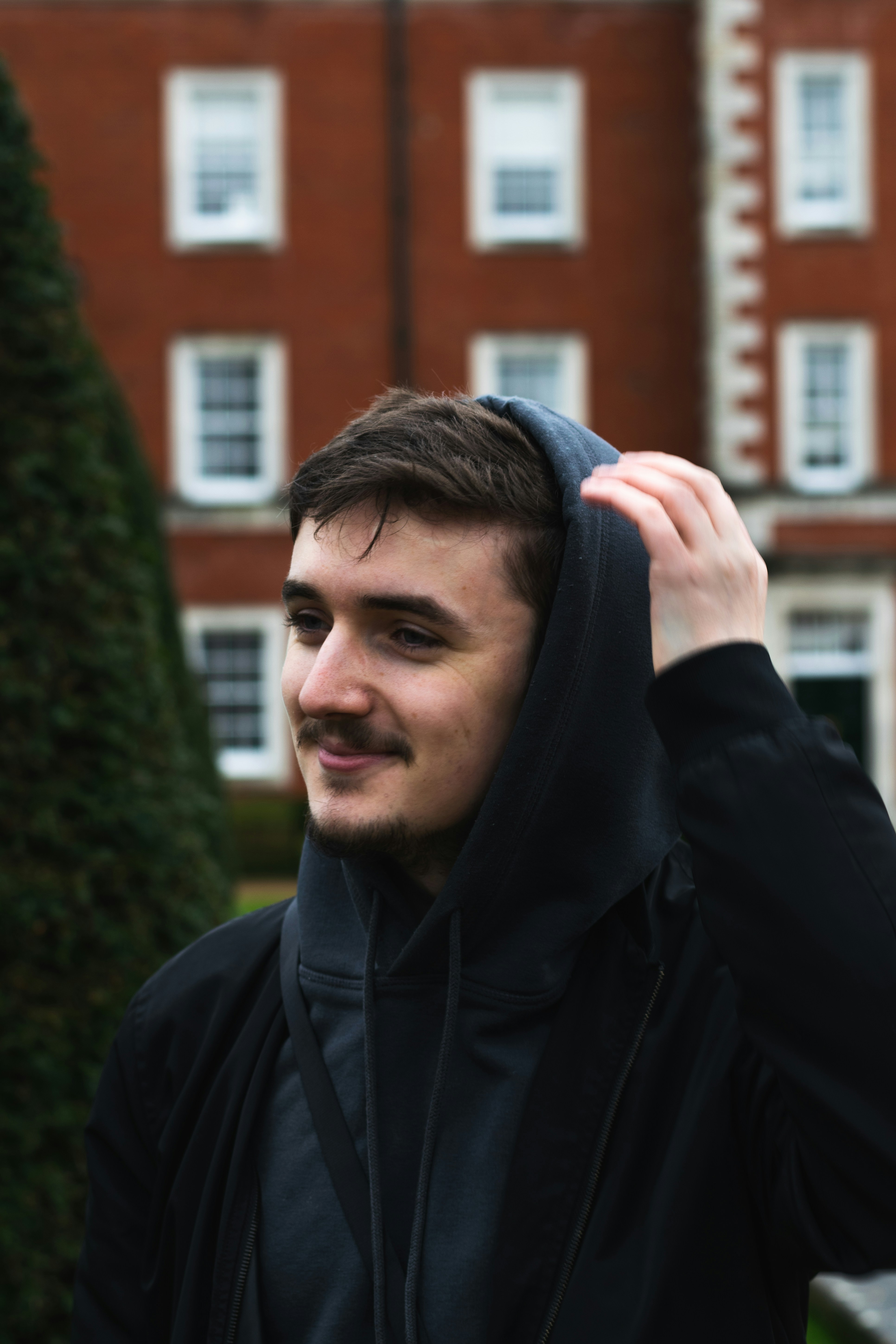 Soft Confession: A Hoodie-Clad Moment by the Red Brick Wall