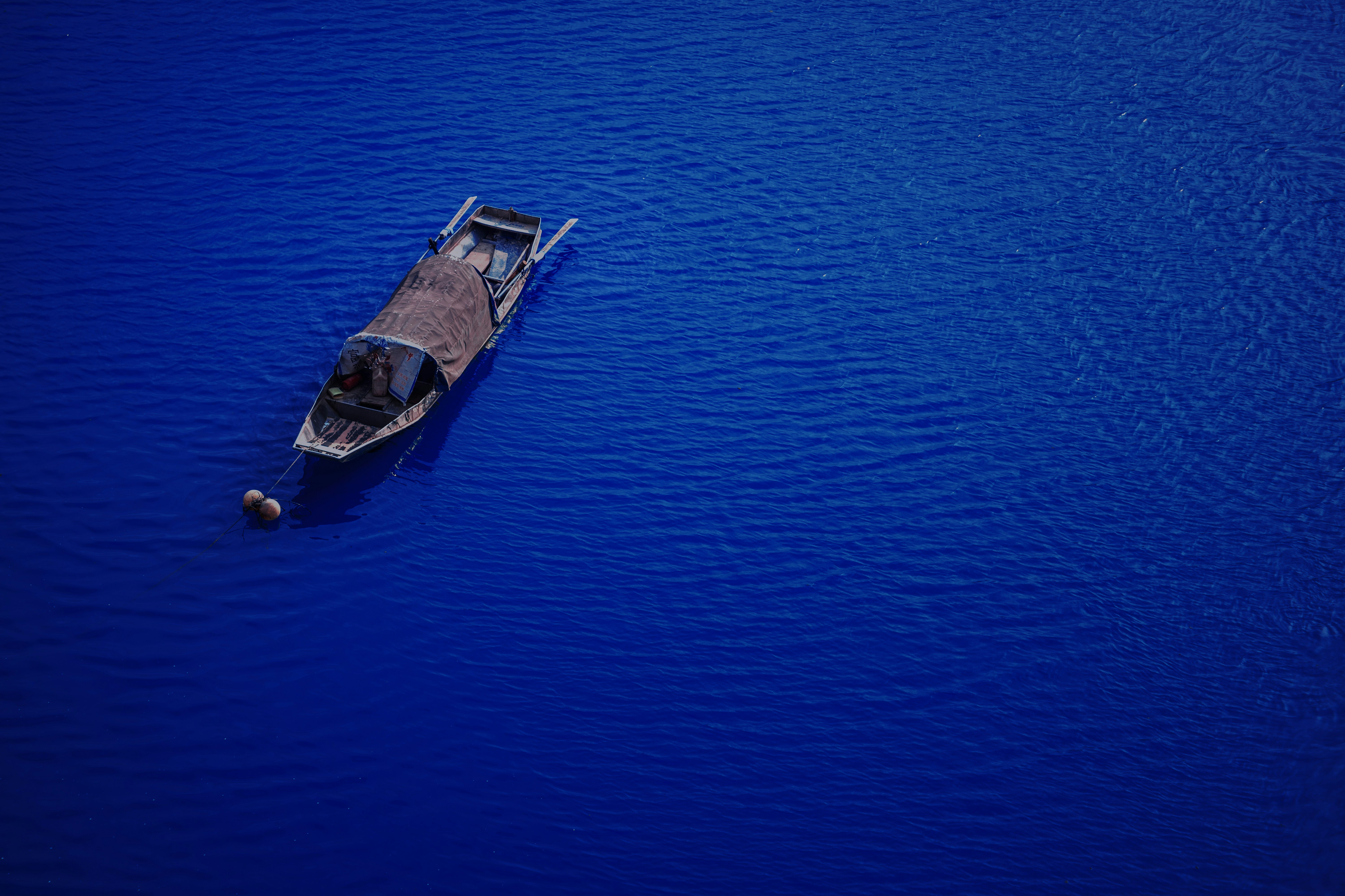  lone wooden boat adrift in cobalt sea