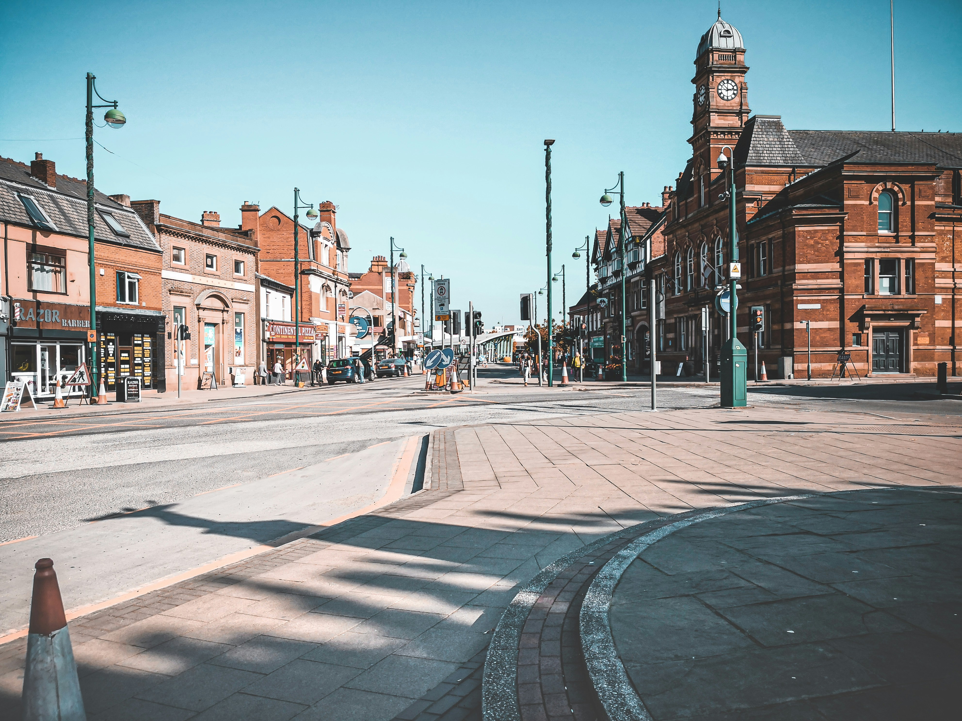 Empty urban street with historic red brick buildings under a clear blue sky.