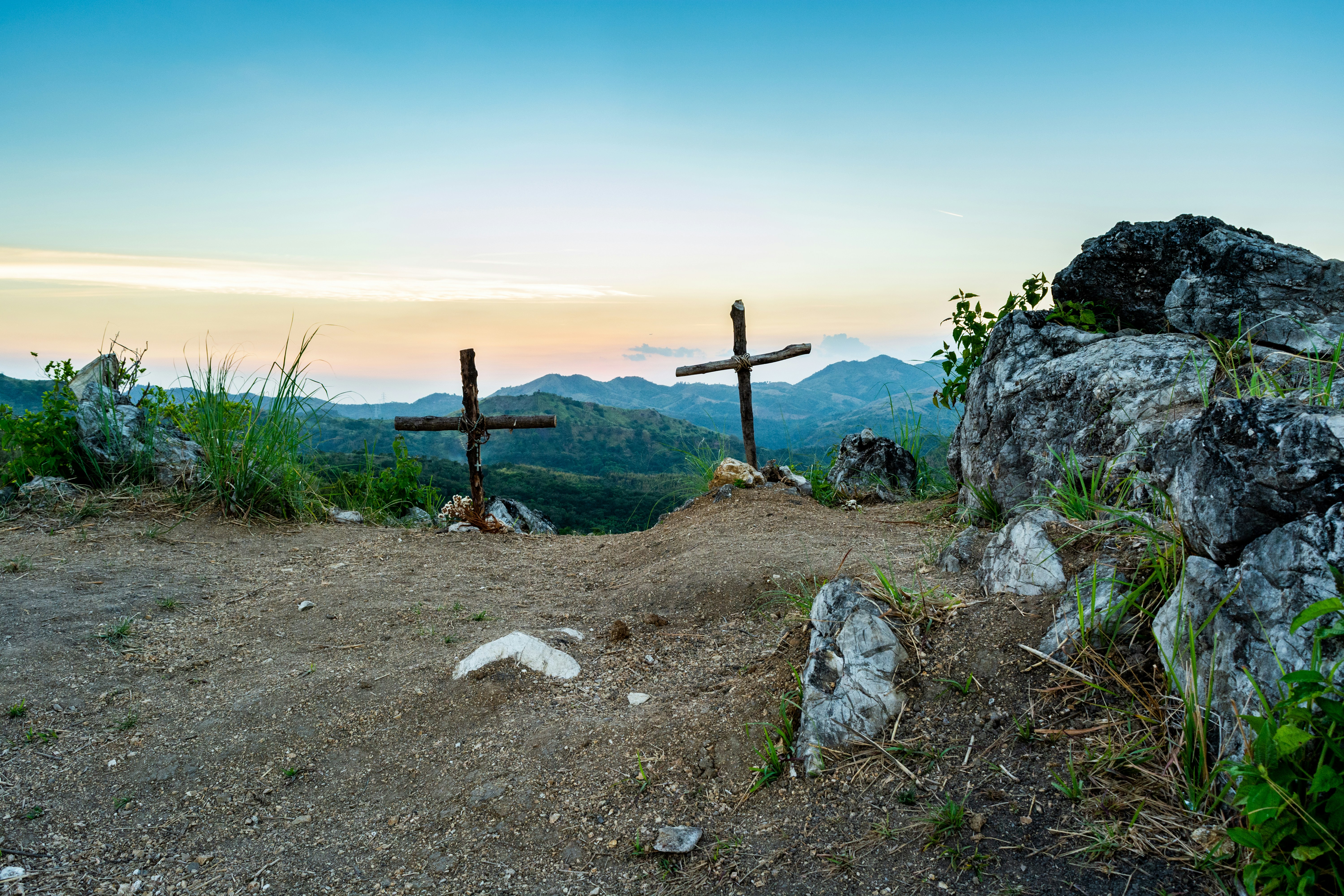 brown wooden cross on gray rock formation under blue sky during daytime