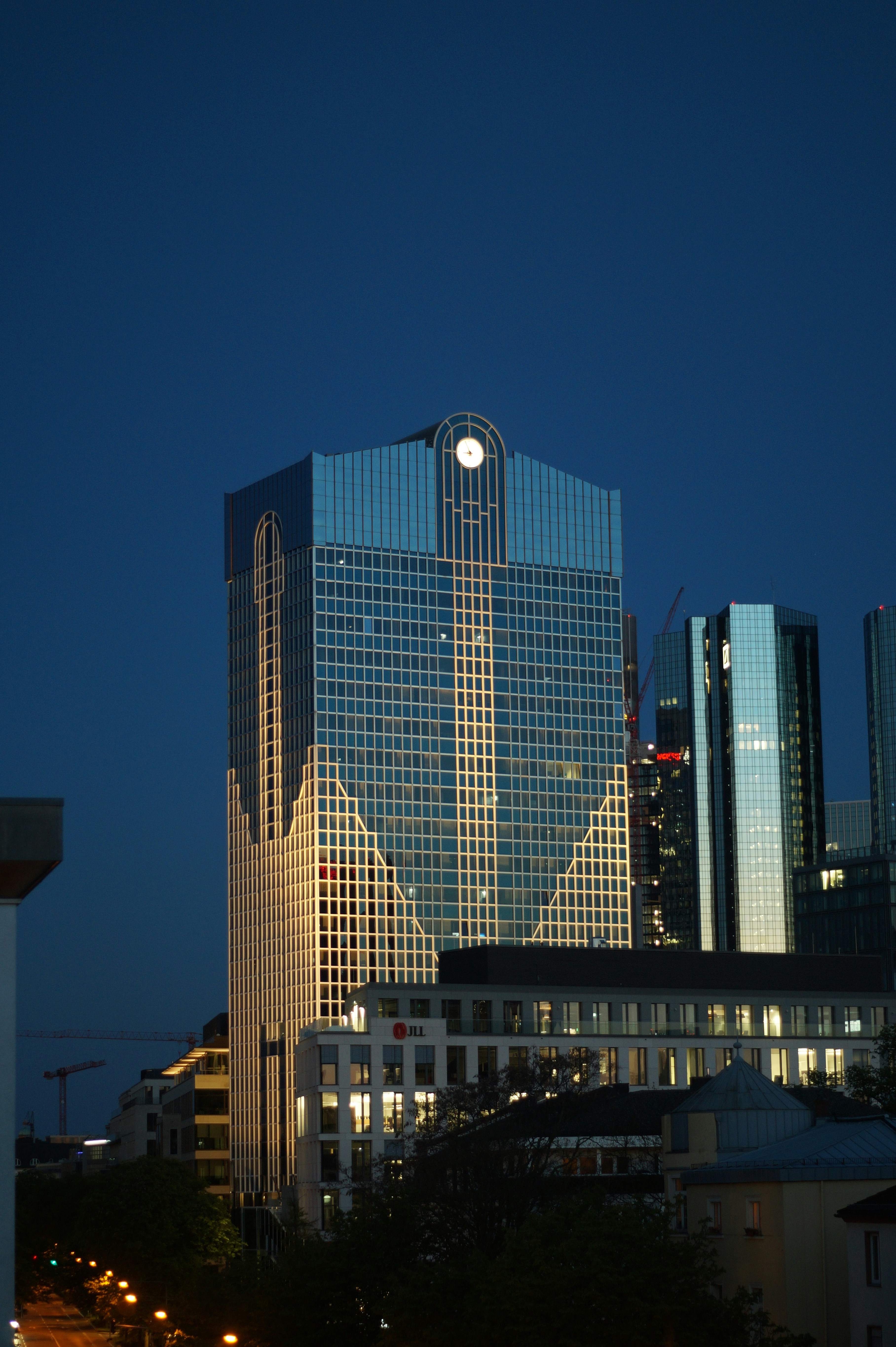 Illuminated skyscraper reflecting city lights against a twilight backdrop, showcasing contemporary architecture.