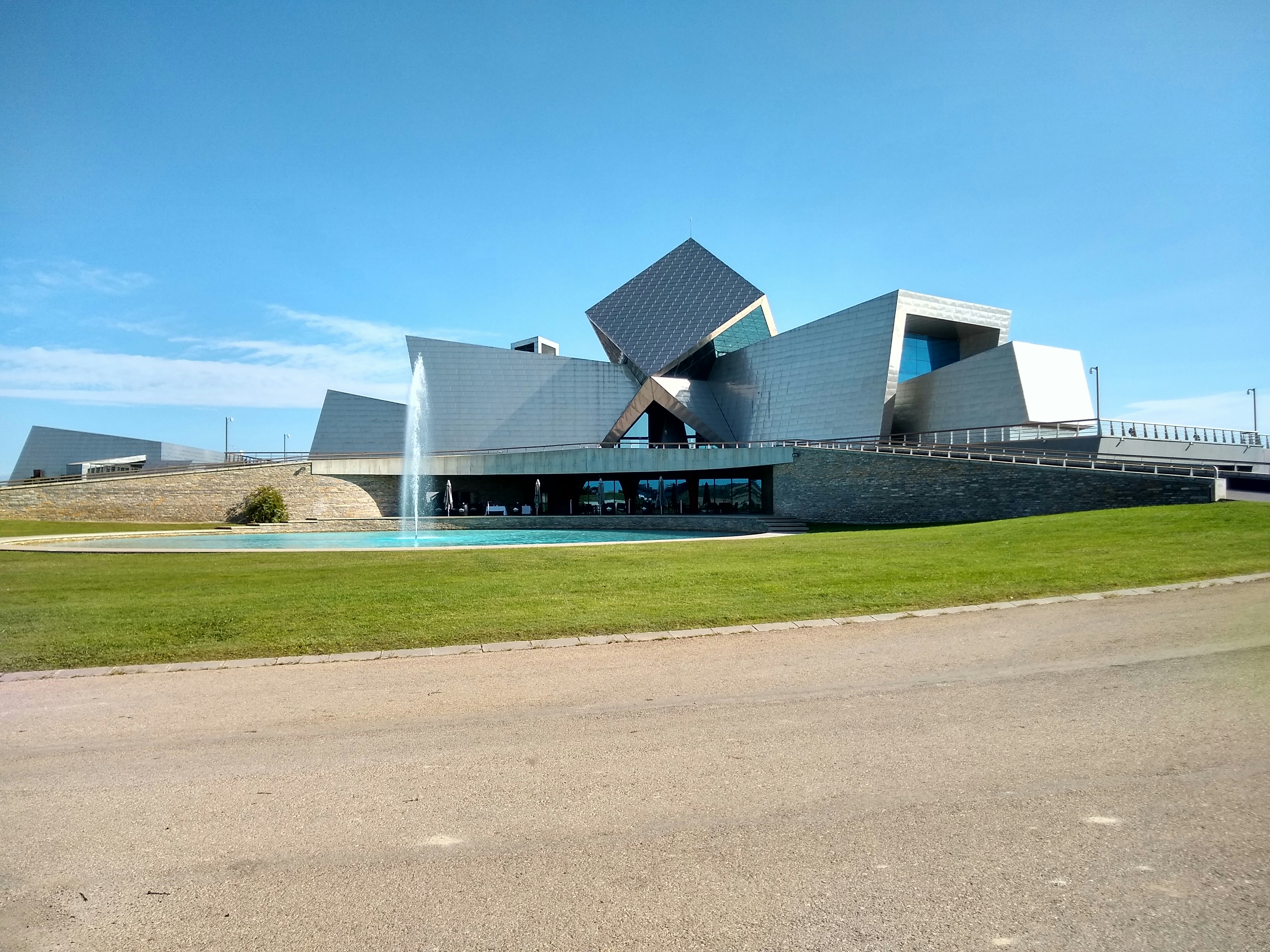 Contemporary building with angular, overlapping metal panels under a clear blue sky.