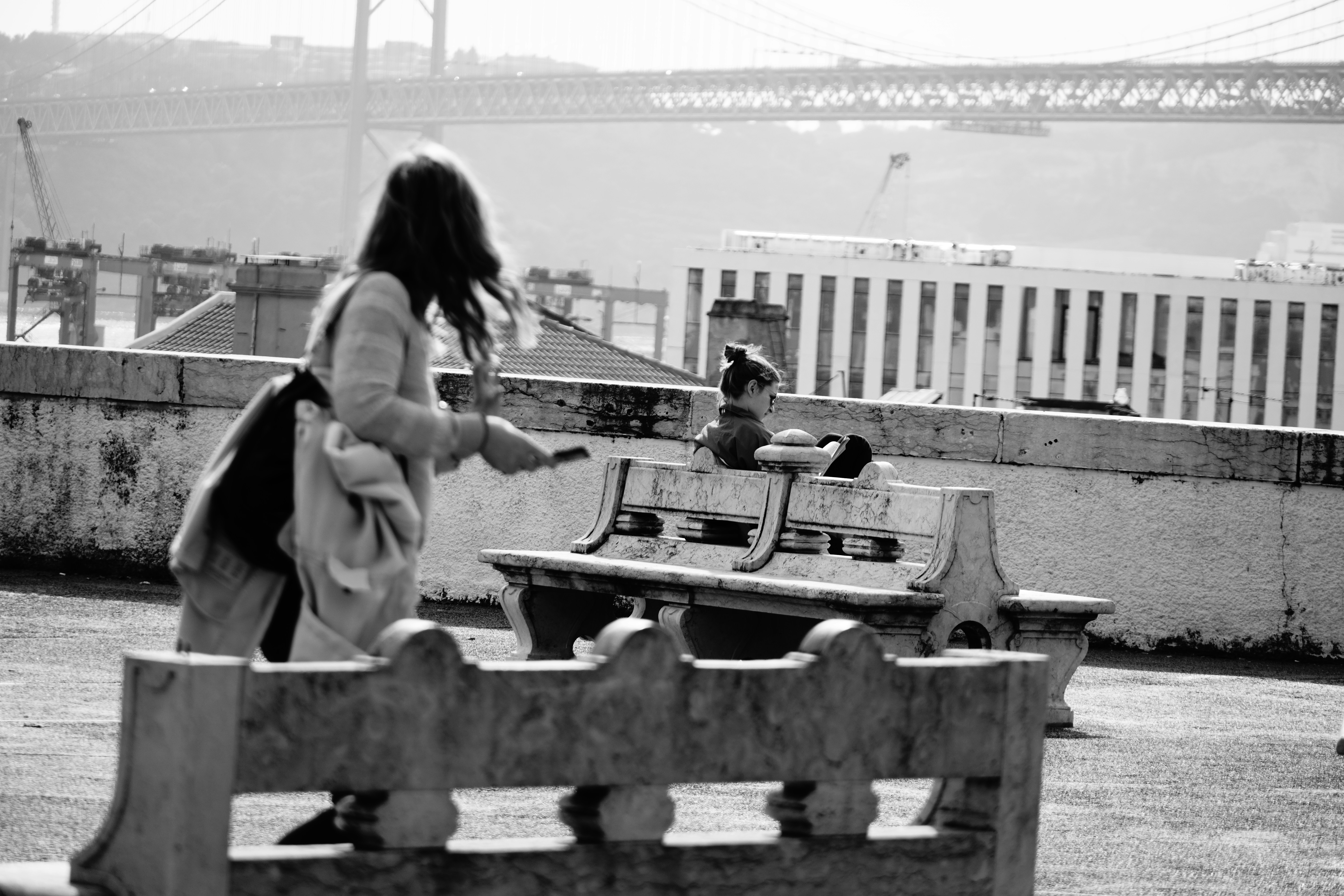 Two figures interact on a rooftop, one in motion and the other seated, framed by urban architecture and distant structures.