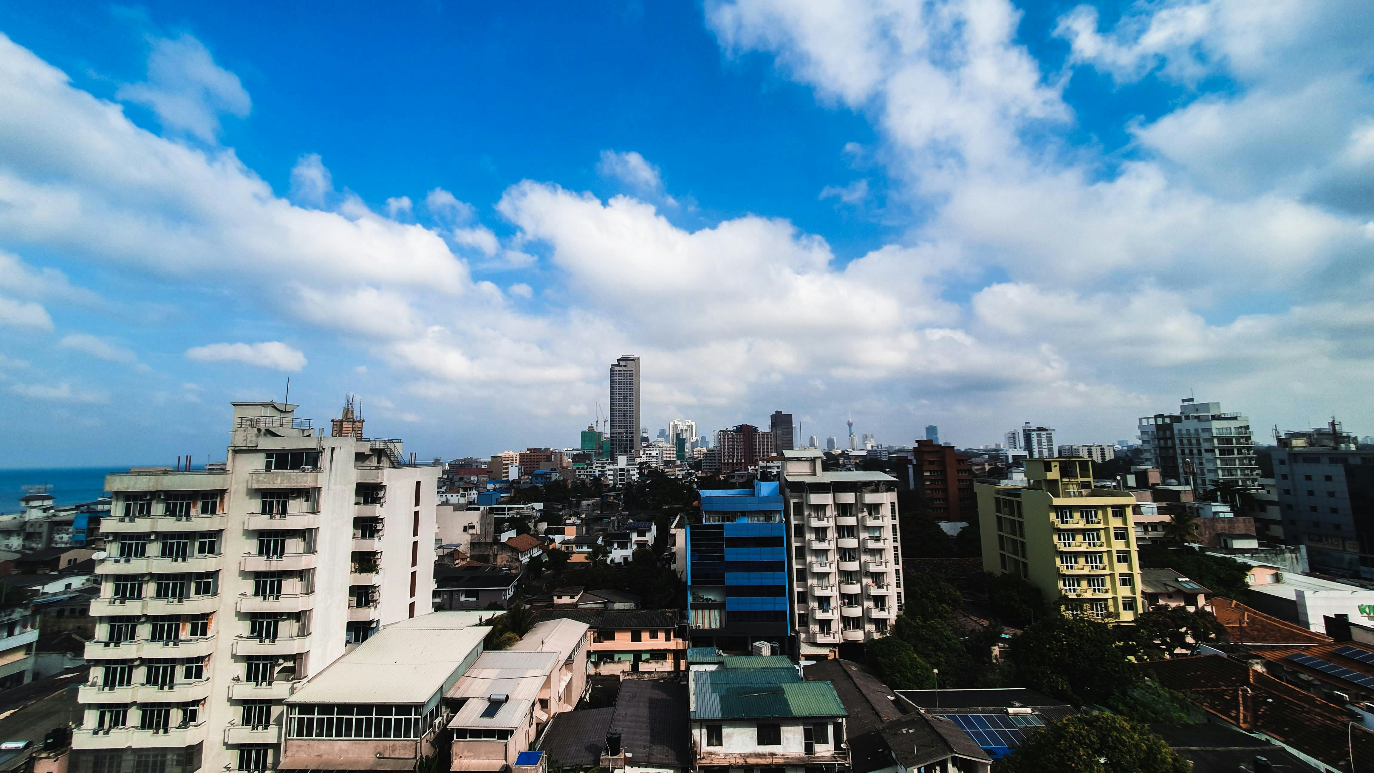 Cityscape with diverse architecture under a vivid blue sky filled with scattered clouds.