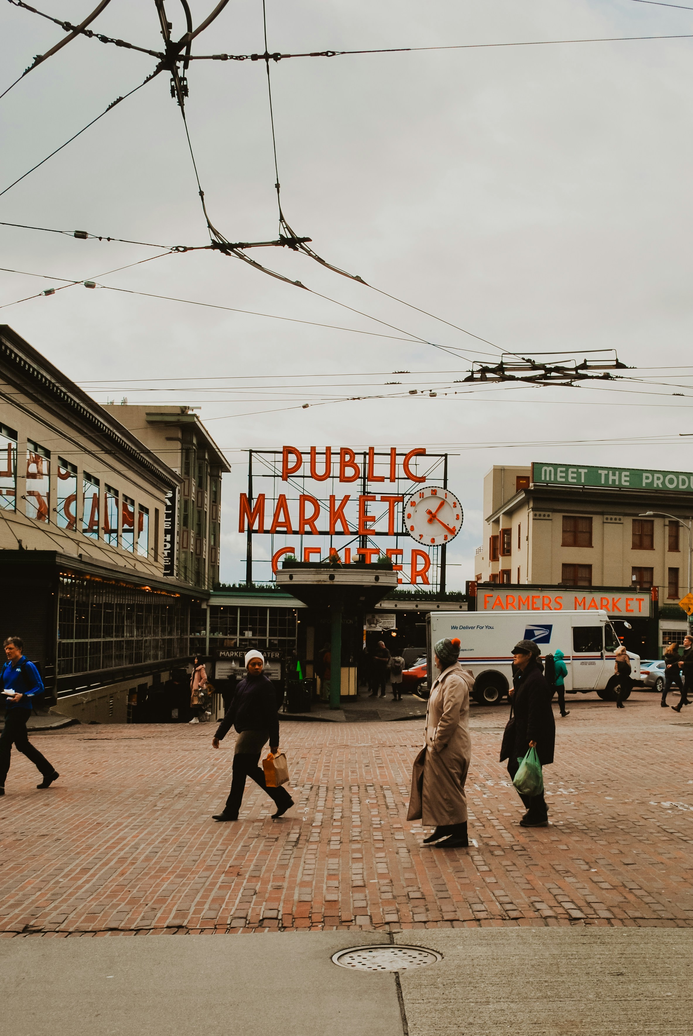 Vibrant market scene at Public Market Center, featuring pedestrians navigating the bustling square with iconic signage in the background.